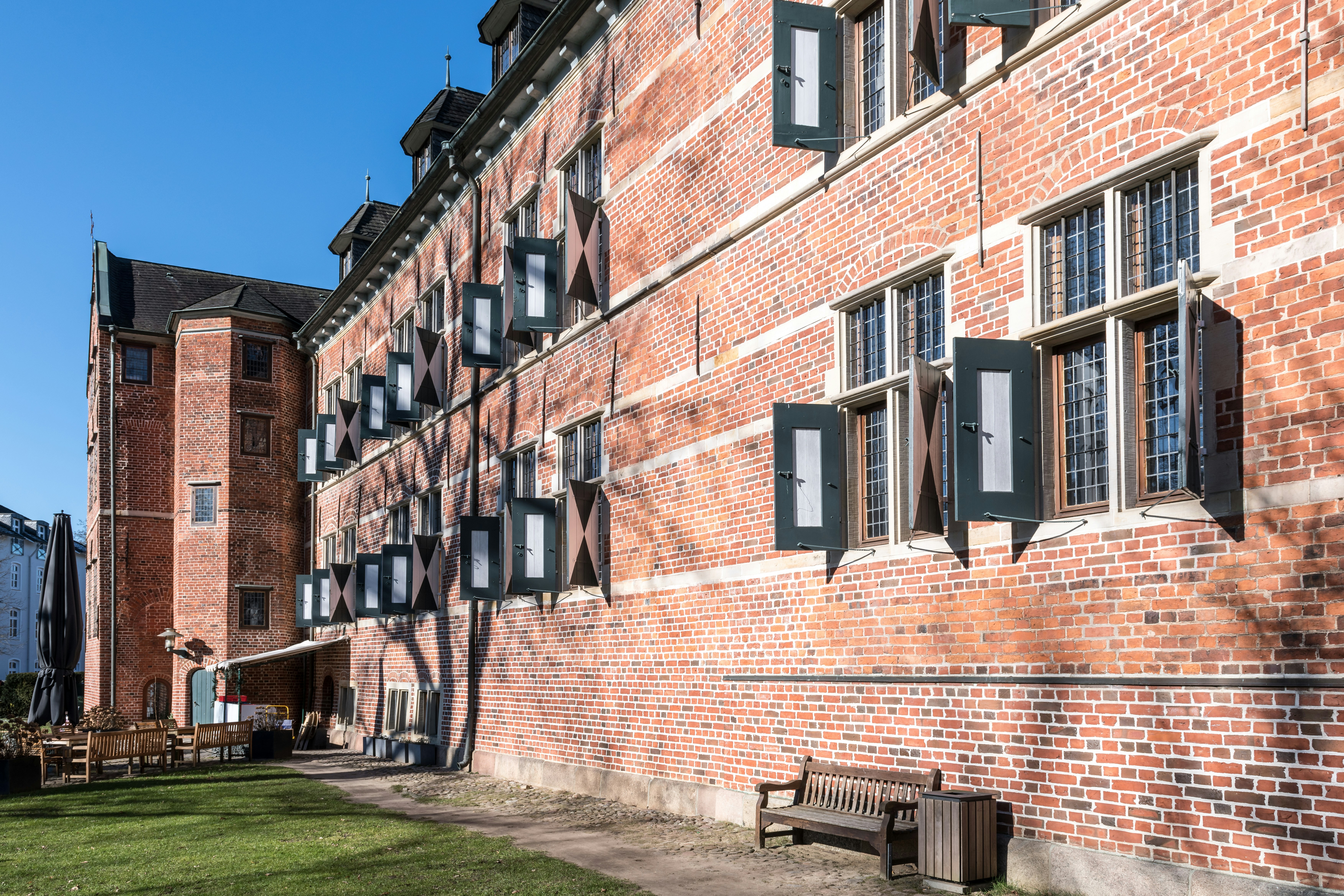 Brick Facade Panorama: Windows, Shutters, and Shadow Play Along a Schoolhouse Wing