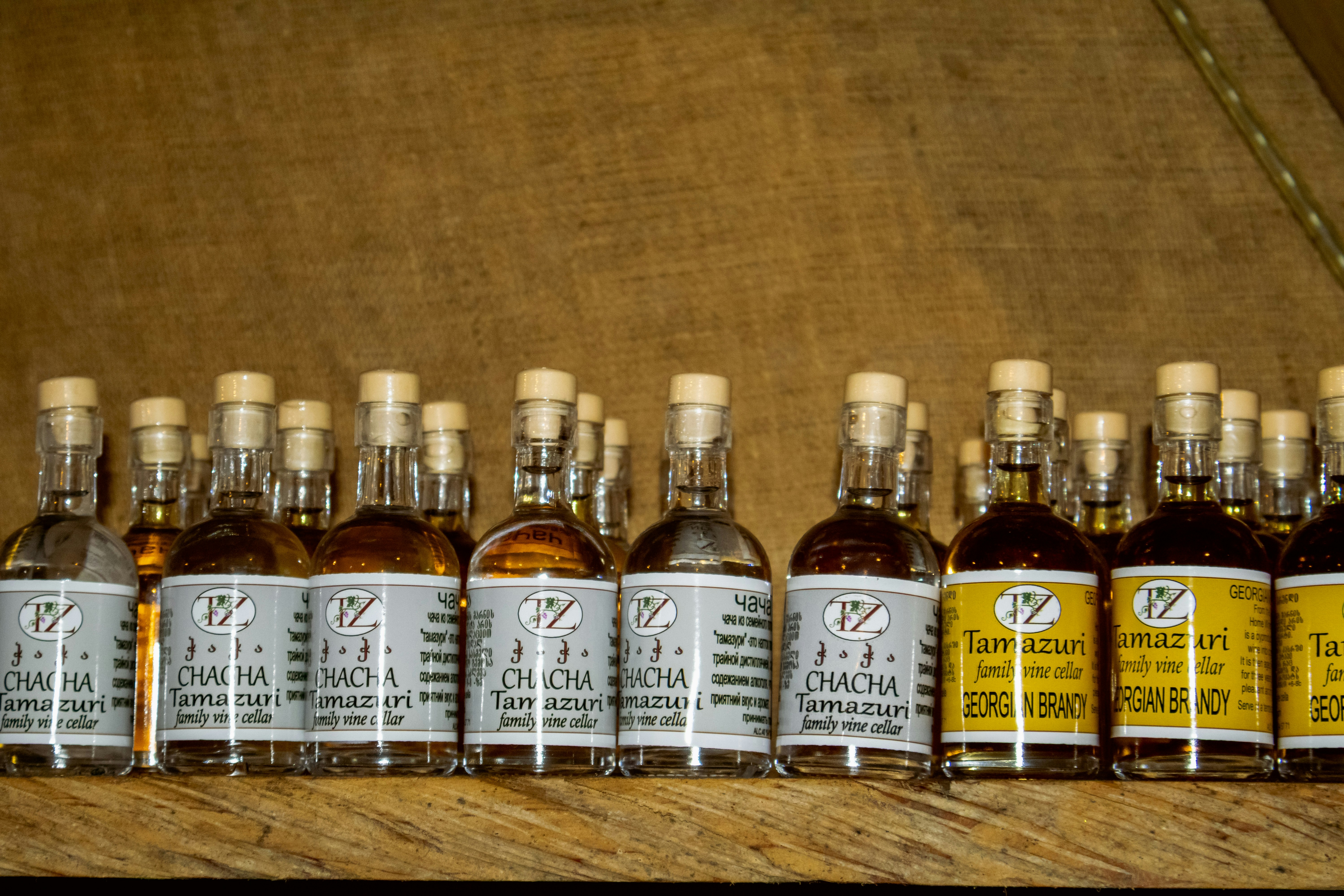 Row of miniature whiskey bottles on a wooden shelf