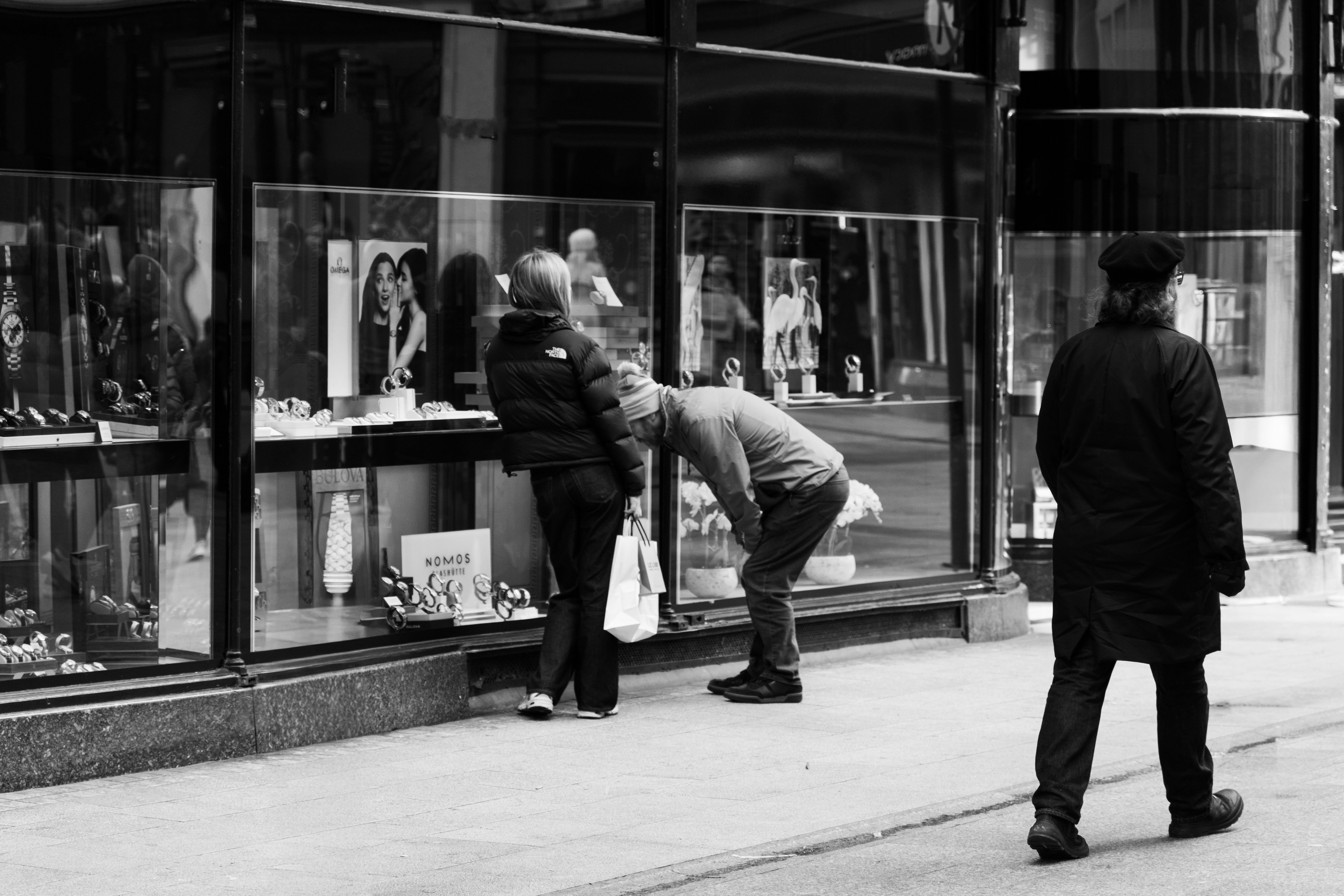 A Curious Merchant Bends Toward a Display in a Quiet City Shop