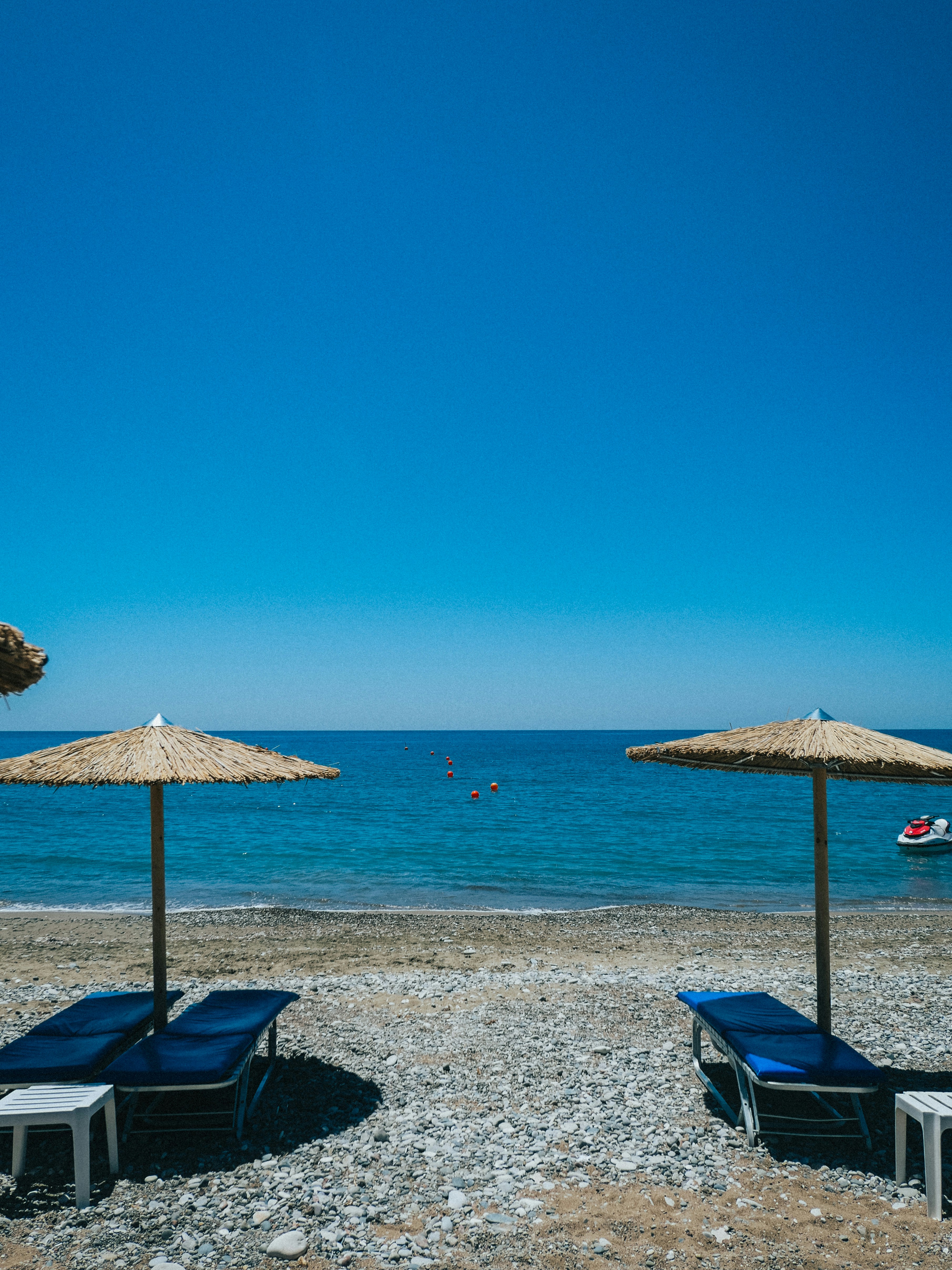 Sunlit Beach Lounge: Striped Blue Cushions Under Straw Umbrellas