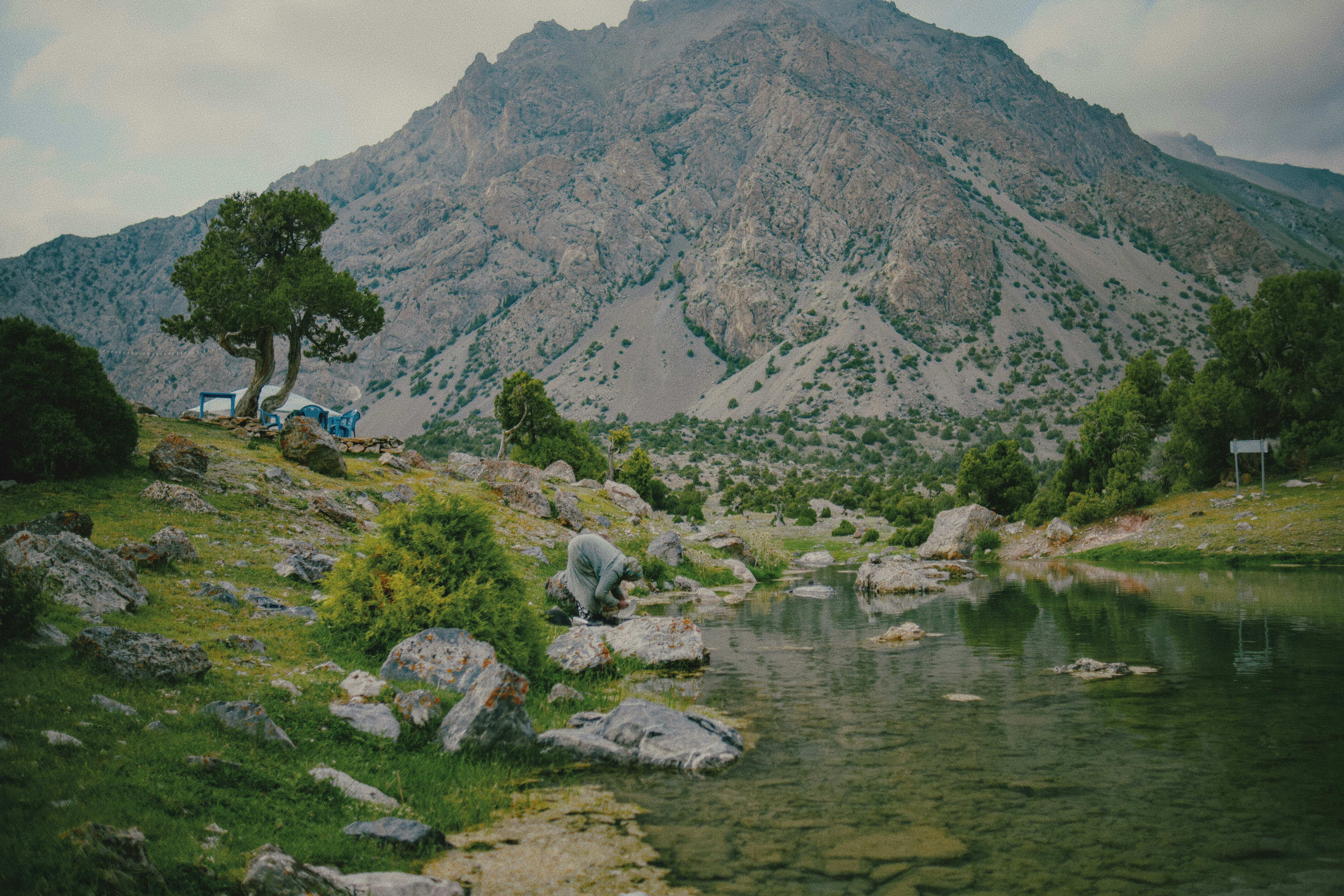Lone Worker by a Mountain Pond under a Rugged Ridge