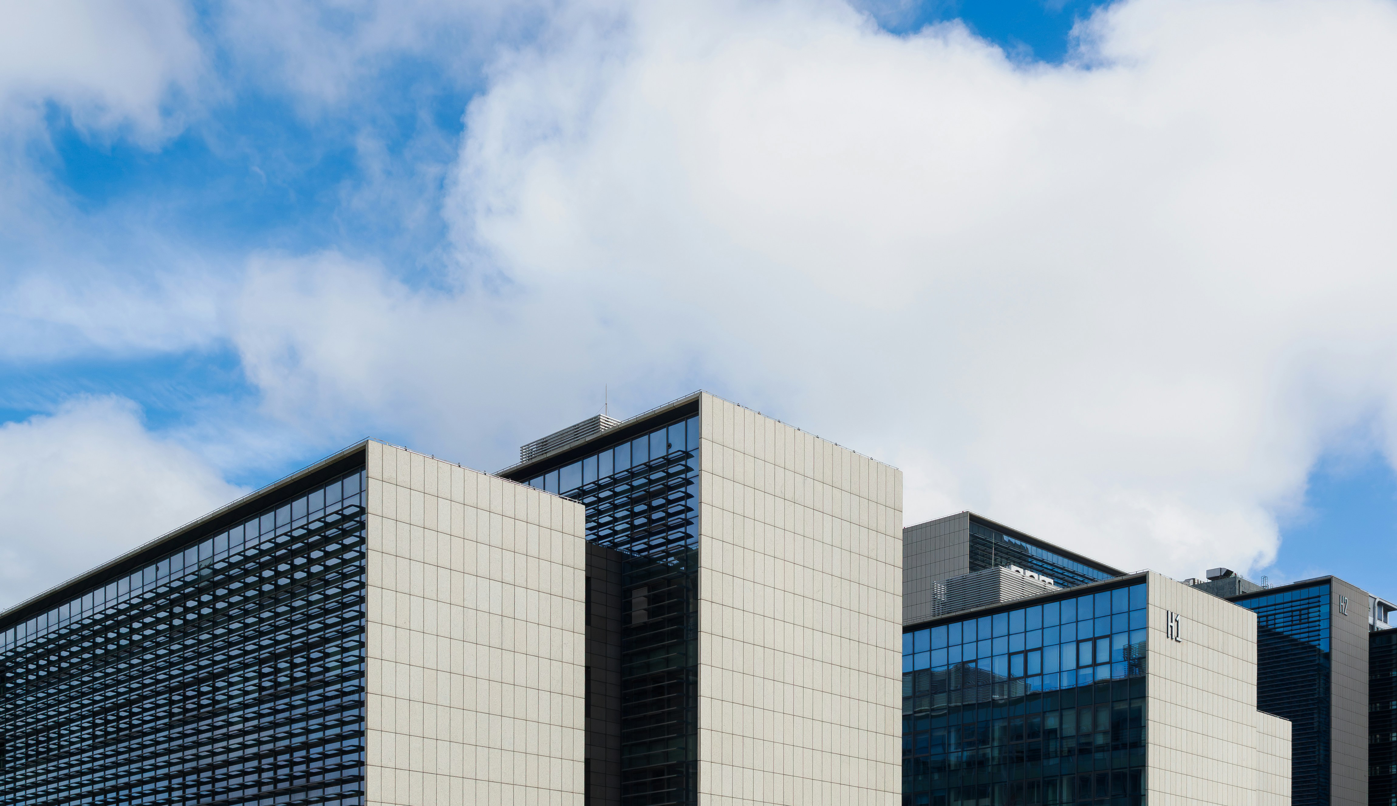 Glazed Facades Ascend: A Geometric Cityscape Under a Bright Sky