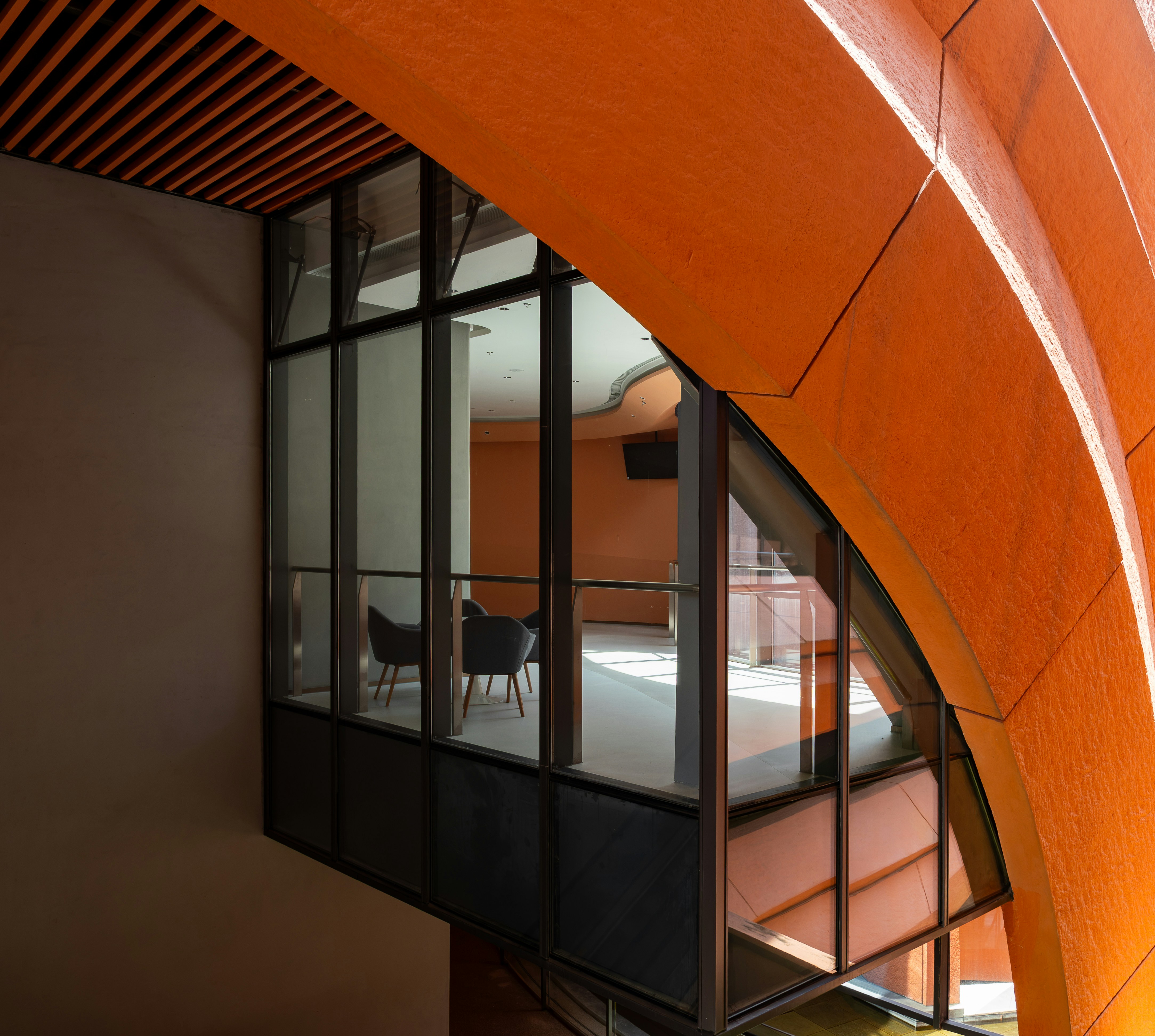 Curved orange arc framing a glass-walled mezzanine