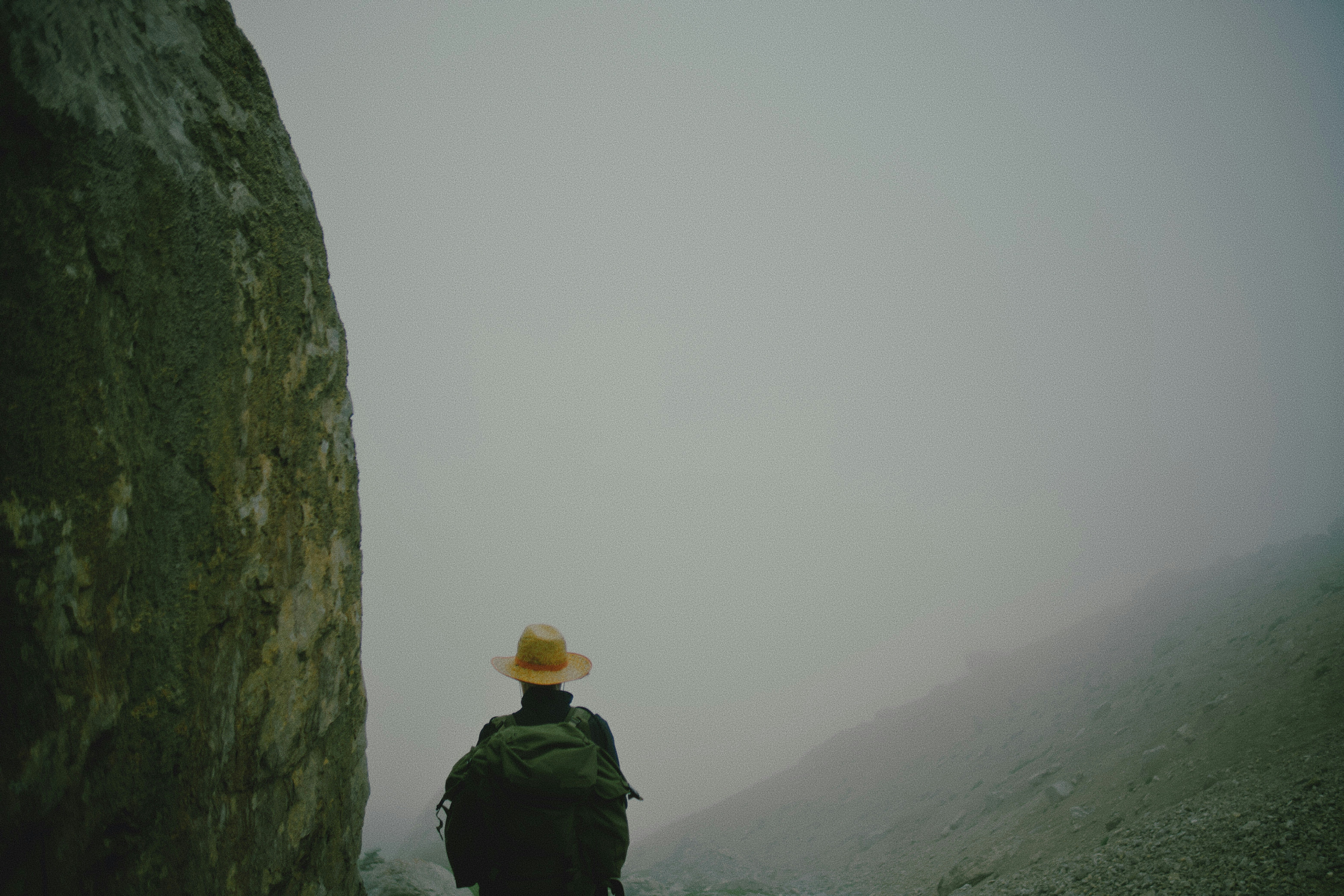 Misty Ascent: A solitary traveler amid green cliff and fog