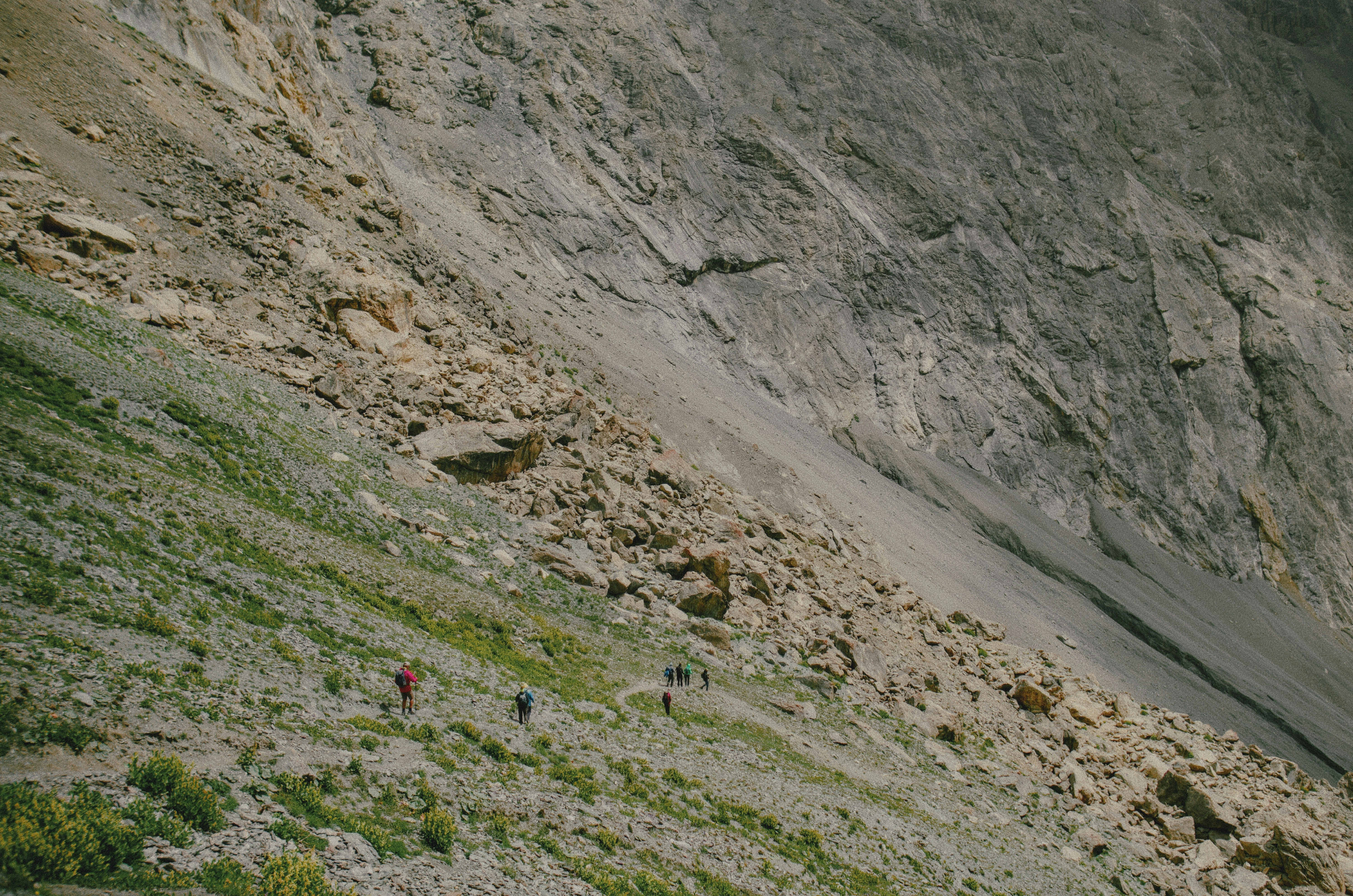Trailblazers on a rocky slope beneath a looming cliff