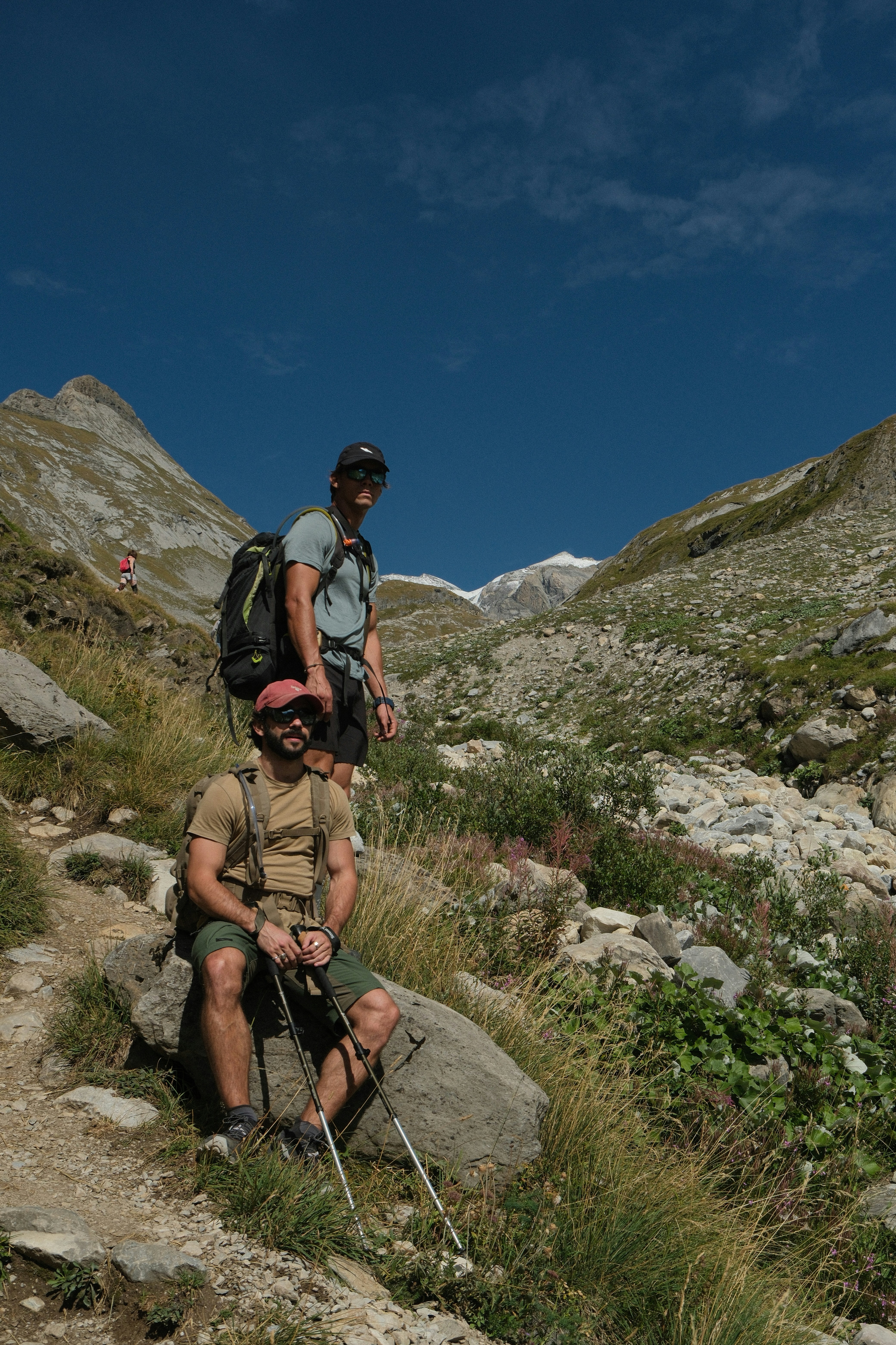Hikers Rest on a Rugged Alpine Path Under a Clear Blue Sky