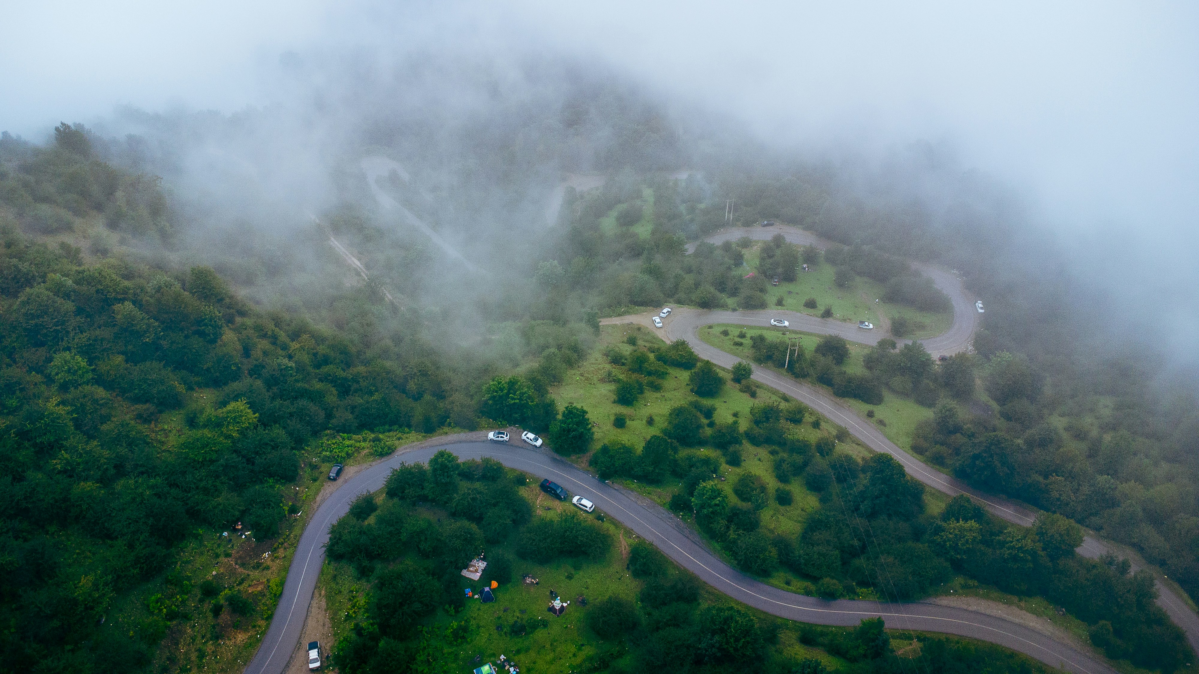 Curved Mountain Road Washes Through Misty Green Switchbacks