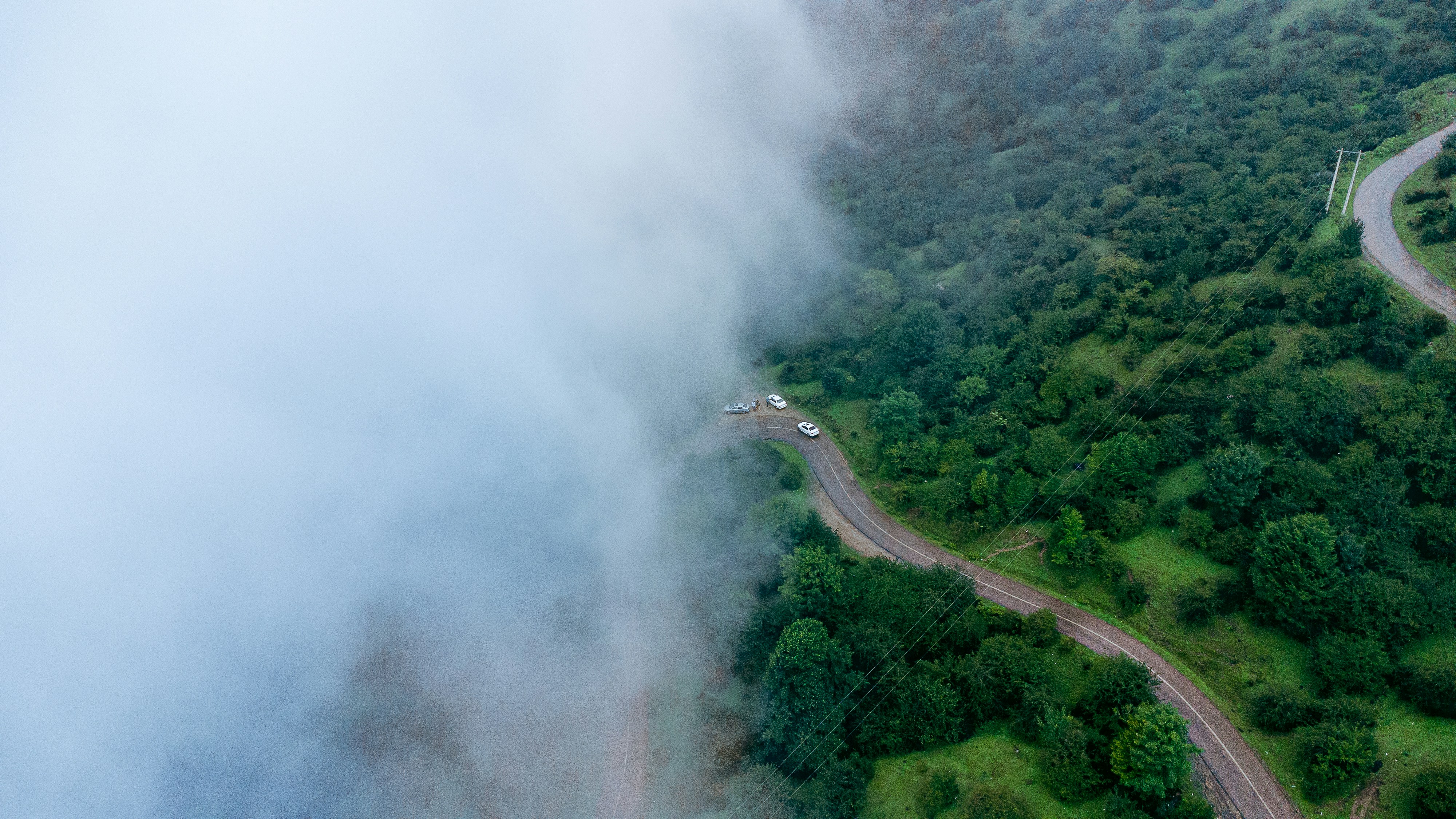 Cloud-veiled Ridge: A Serpentine Road Unfolds Through Verdant Slopes