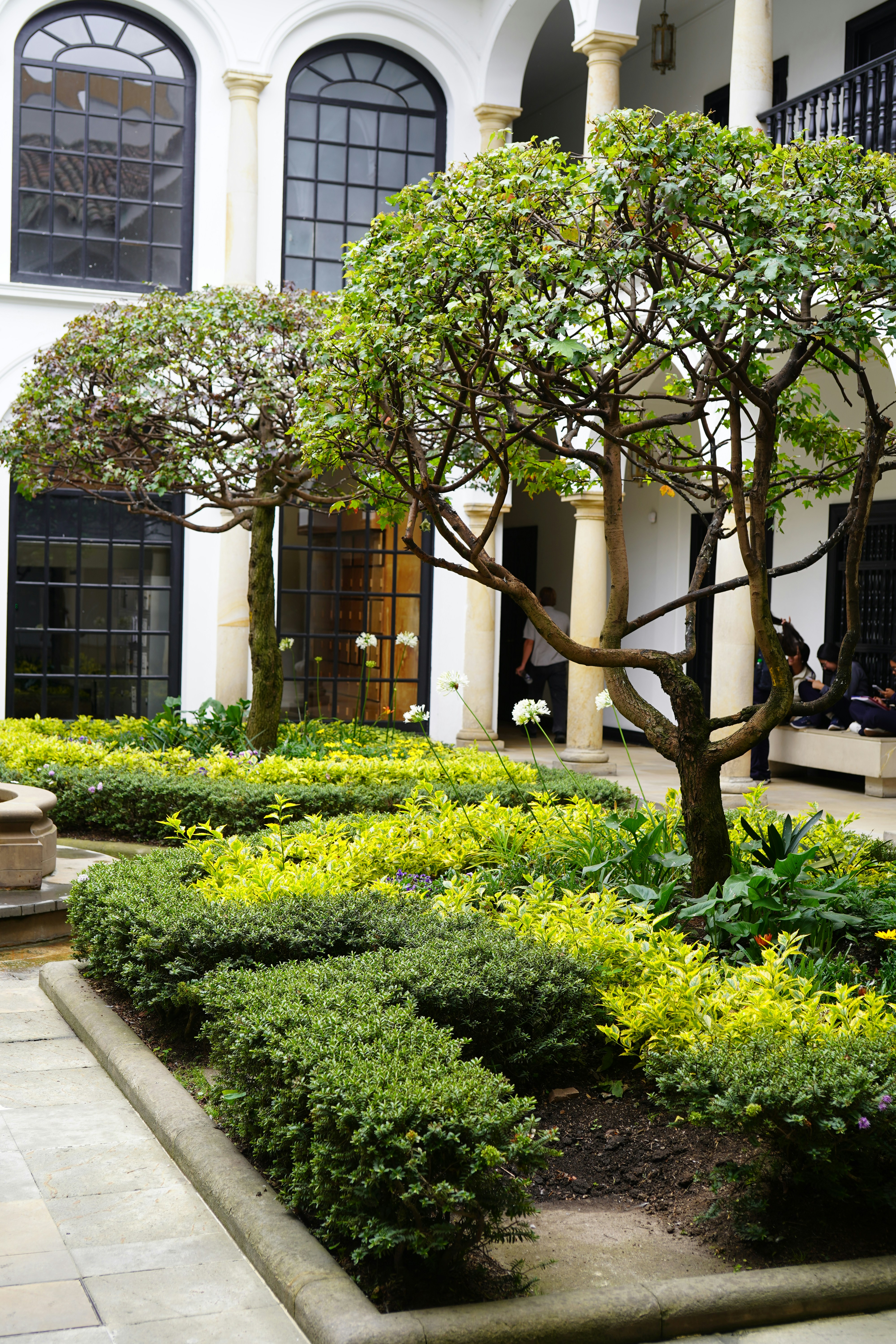 Garden Courtyard with Trimmed Trees and Archwayed Architecture