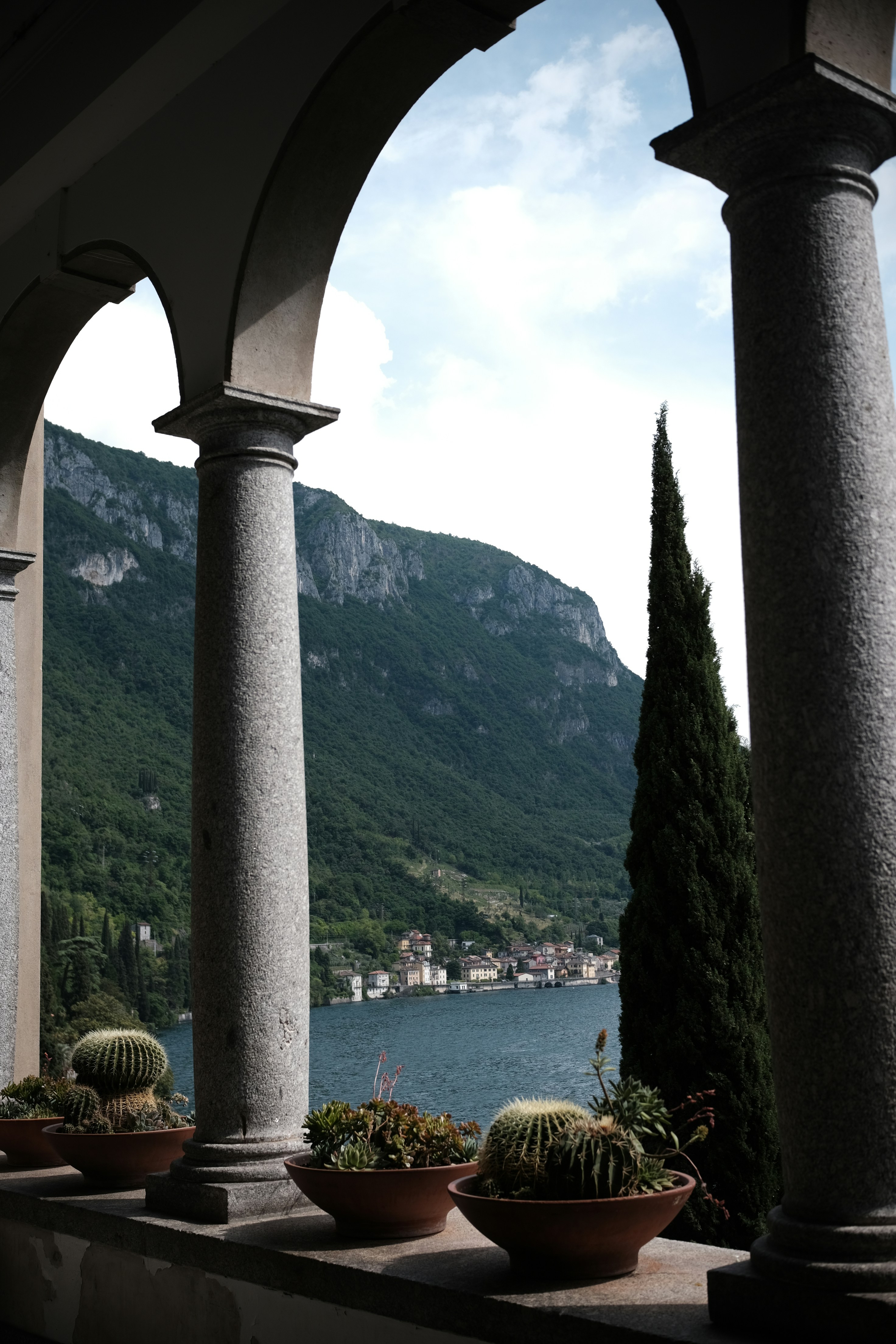 Arched Balcony Overlooking a Lake Village with Tall Cypress