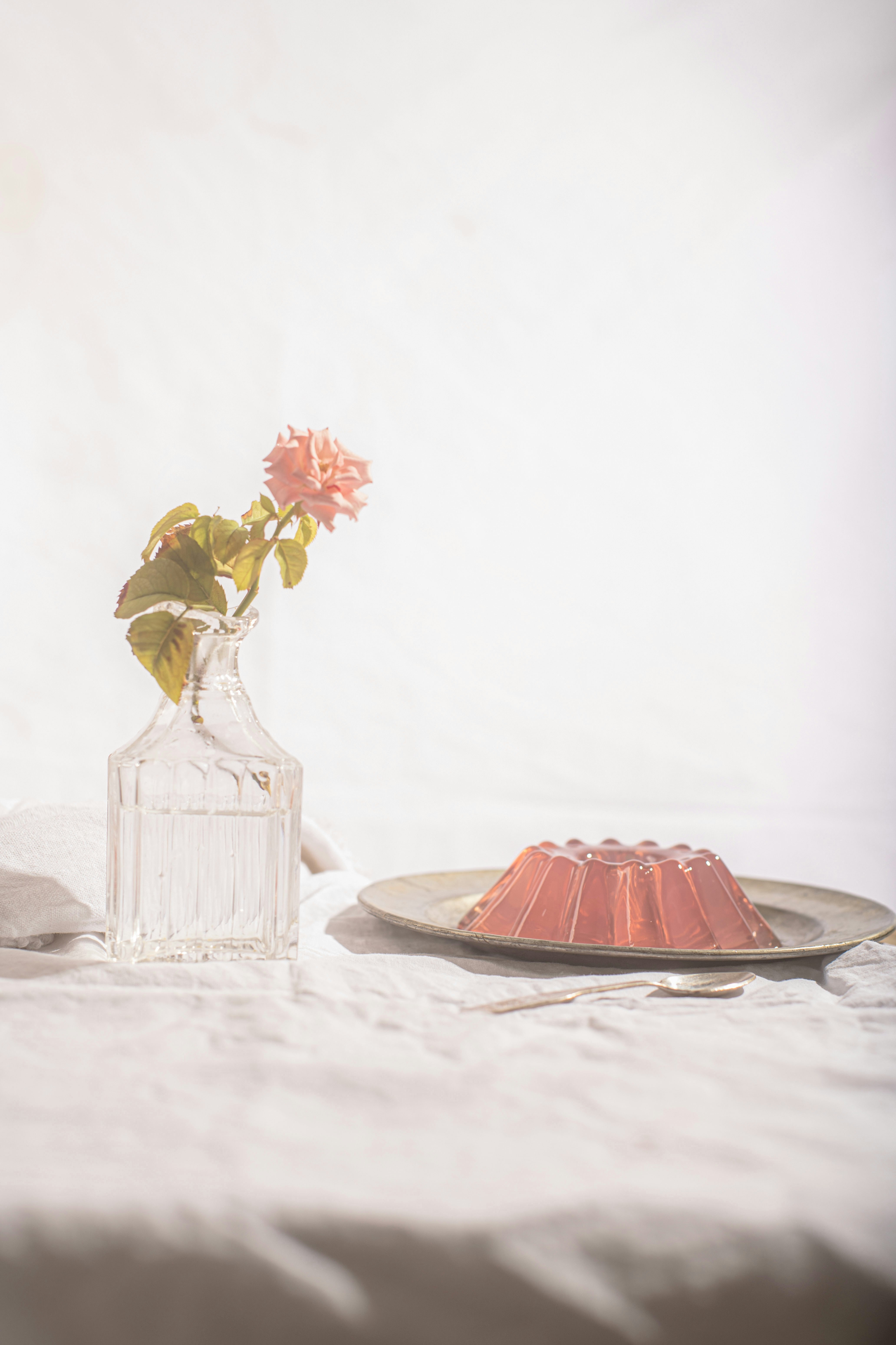 Gentle Still Life: A Rose in Glass and a Red Mold Pan on White Linen