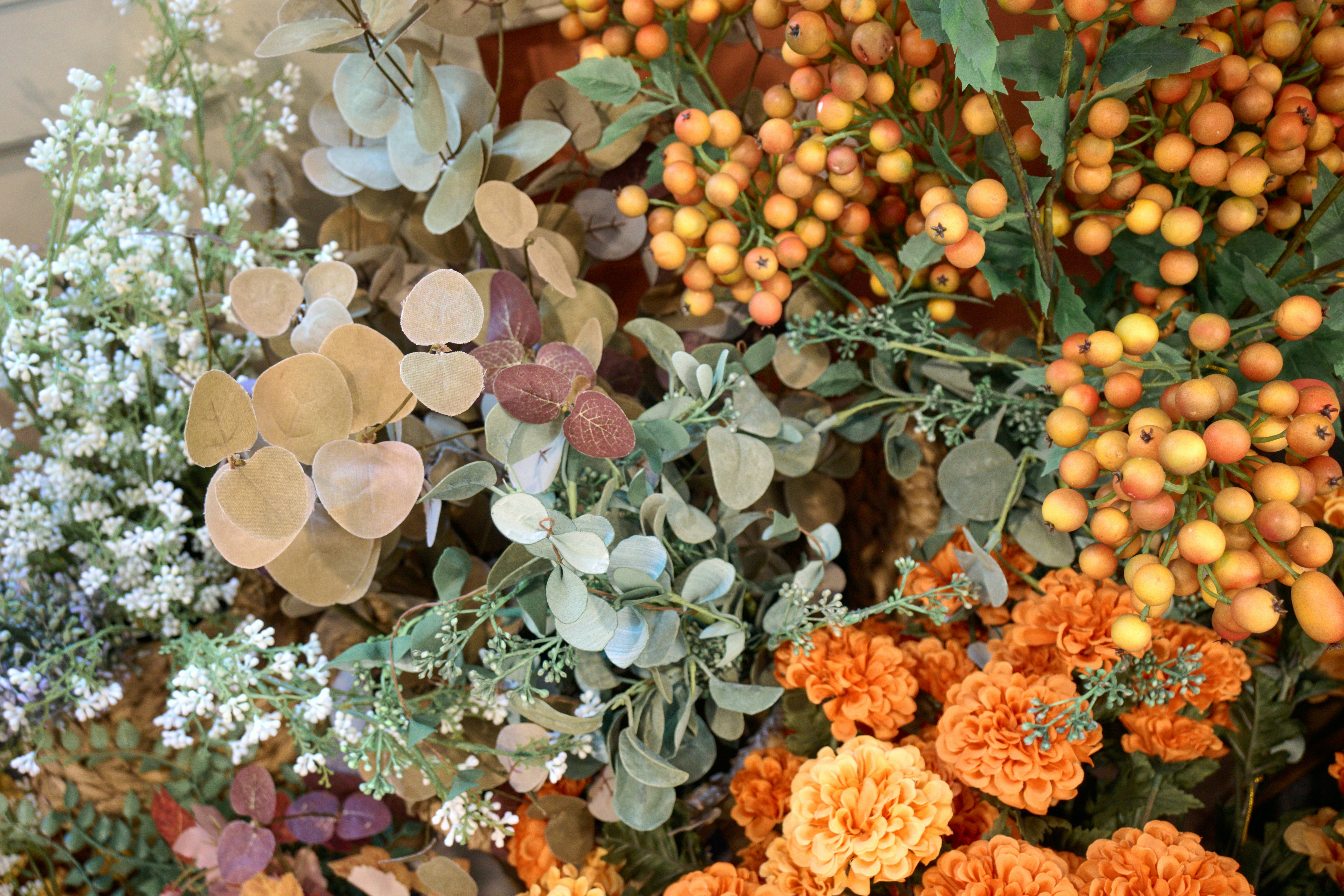 A vibrant arrangement of orange blossoms, eucalyptus, and golden-orange berries forming a lush floral collage.