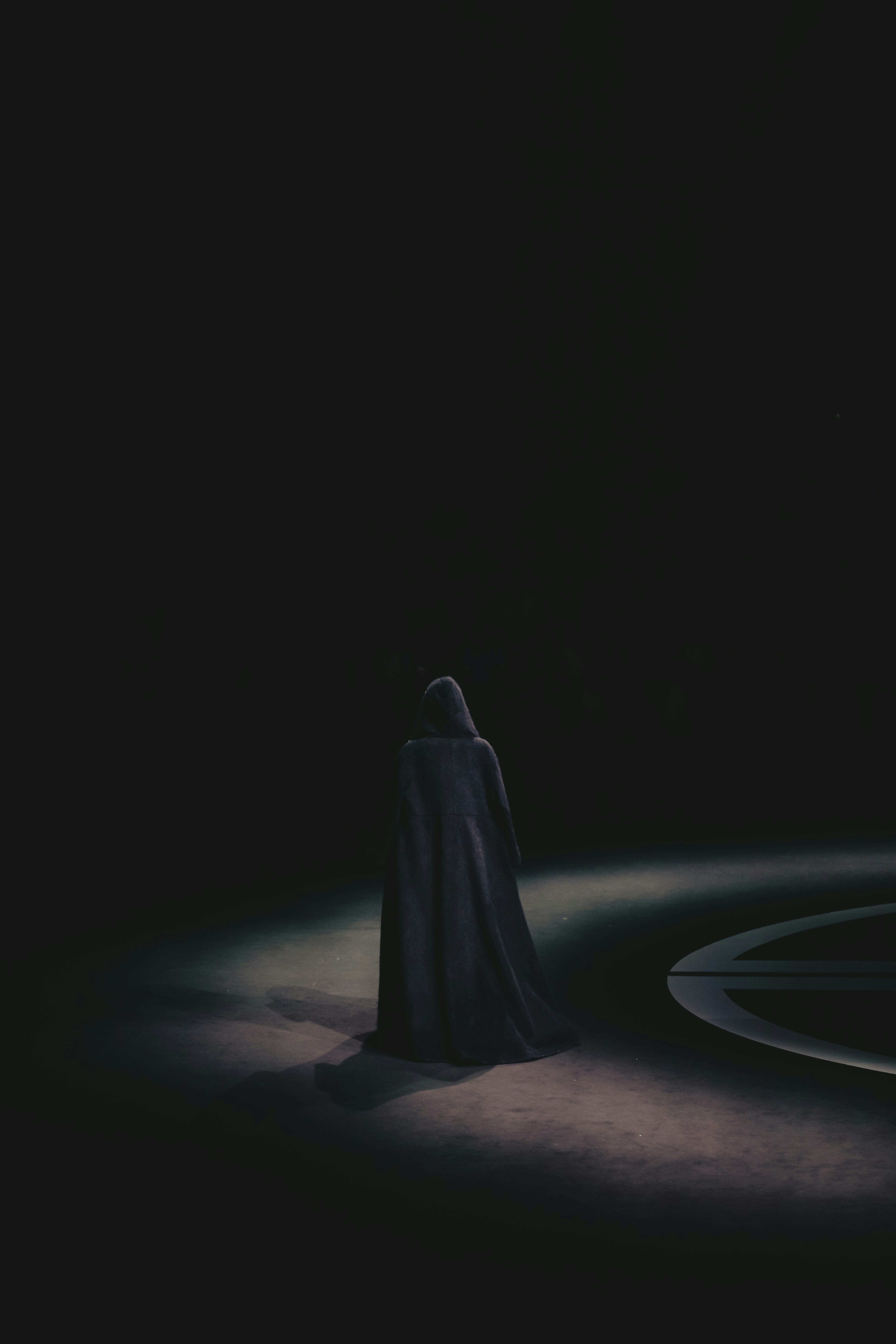 Silhouette of a Cloaked Figure on a Spotlighted Stage