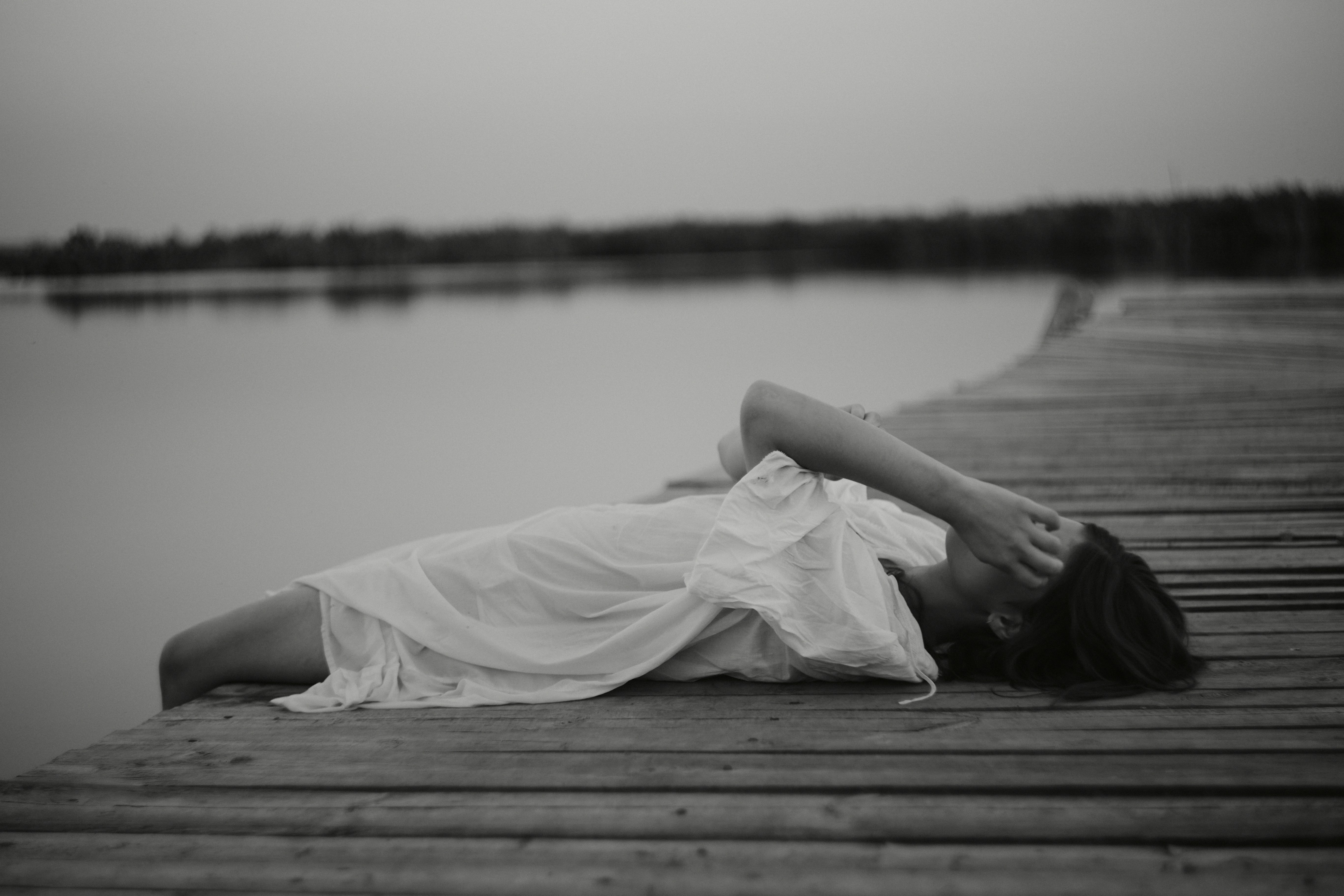 Silhouette of Quiet Wake: A Woman Repose on a Weathered Dock