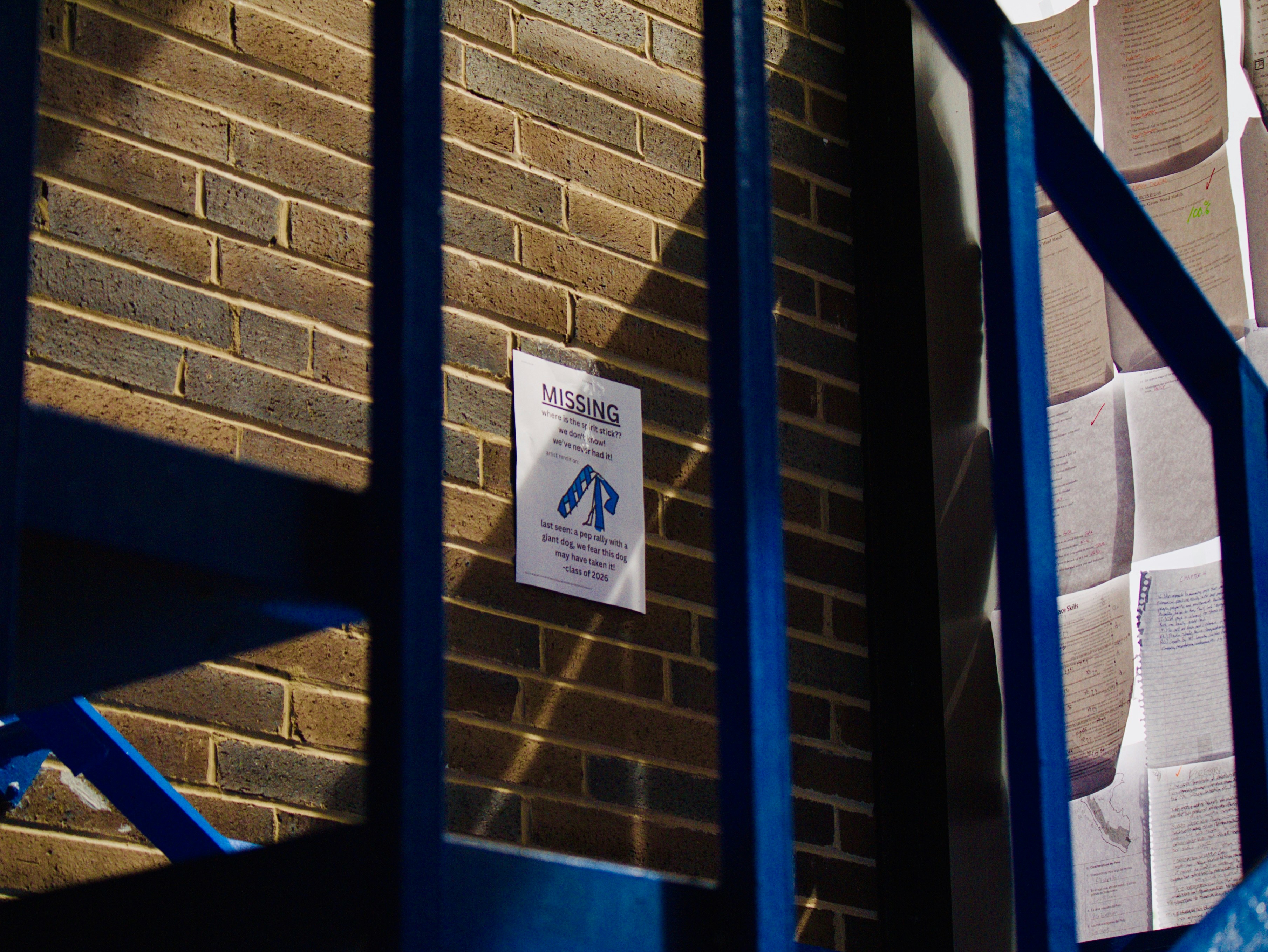 Missing Notice on a Brick Wall Behind Blue Railings