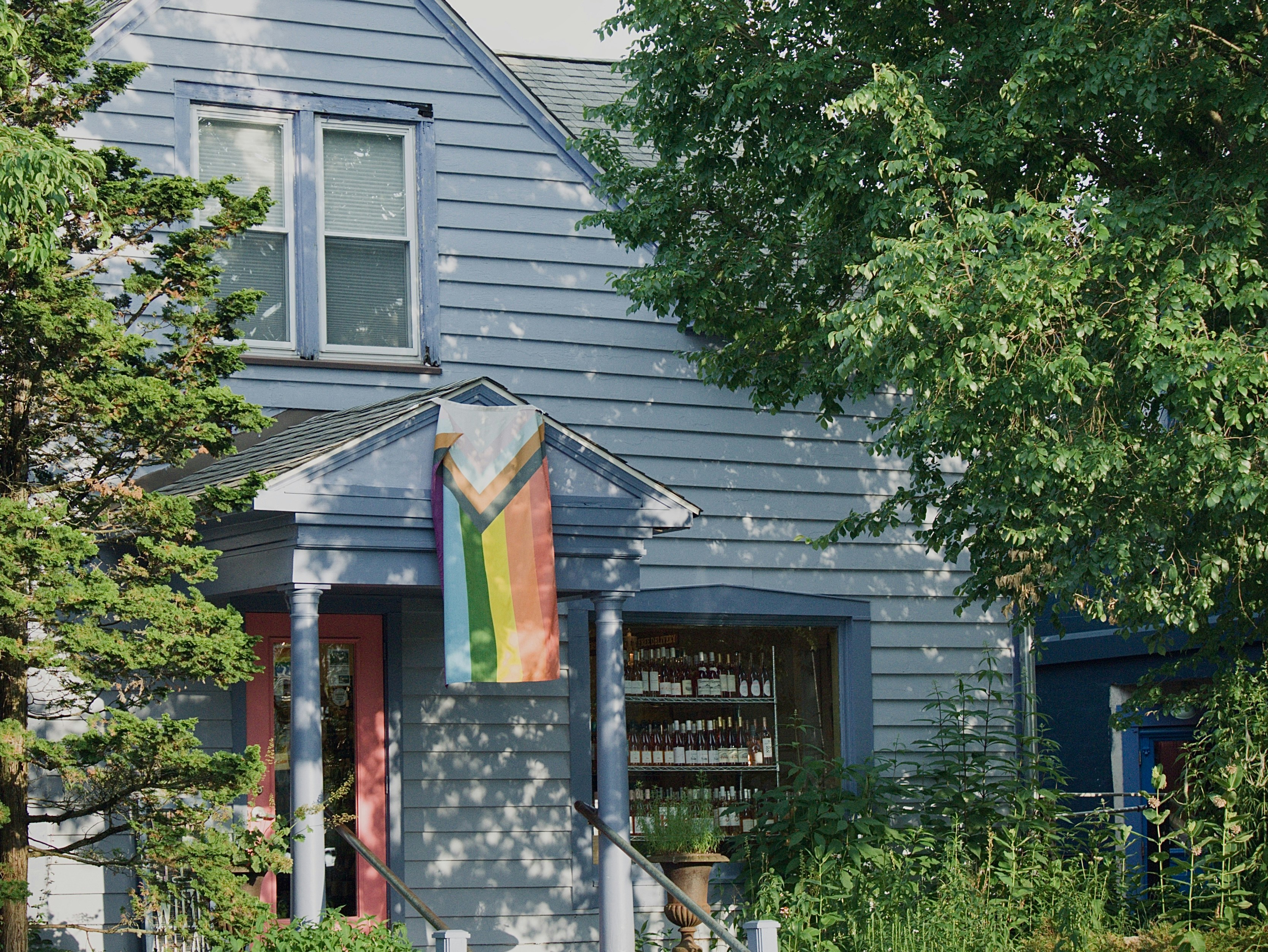 Rainbow Banner Over a Blue House: Quiet Pride by the Entrance