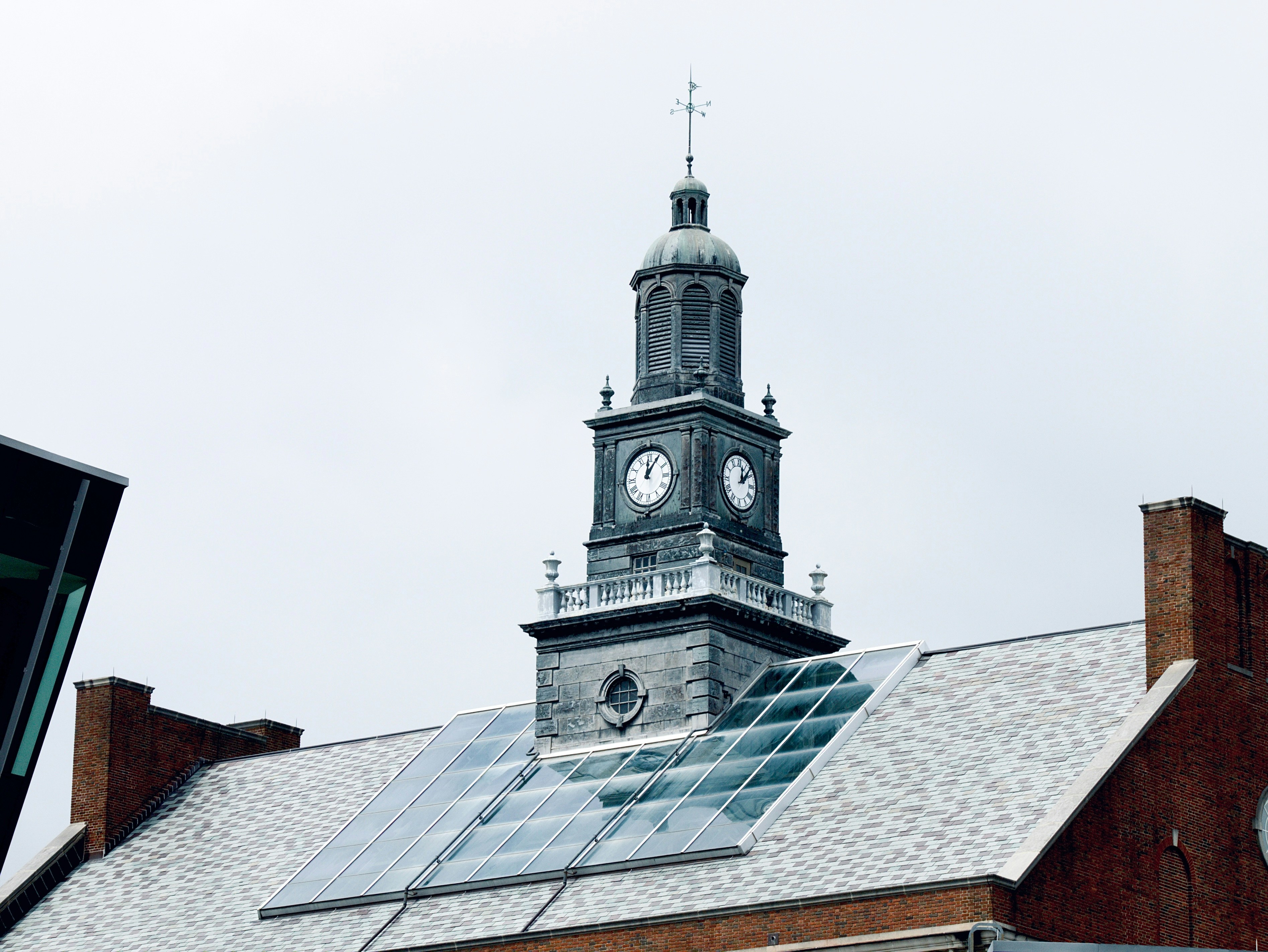 Clocktowering structure with glass skylights atop a brick roofline; urban architecture and muted sky. A skyline focus on architectural details rather than people.