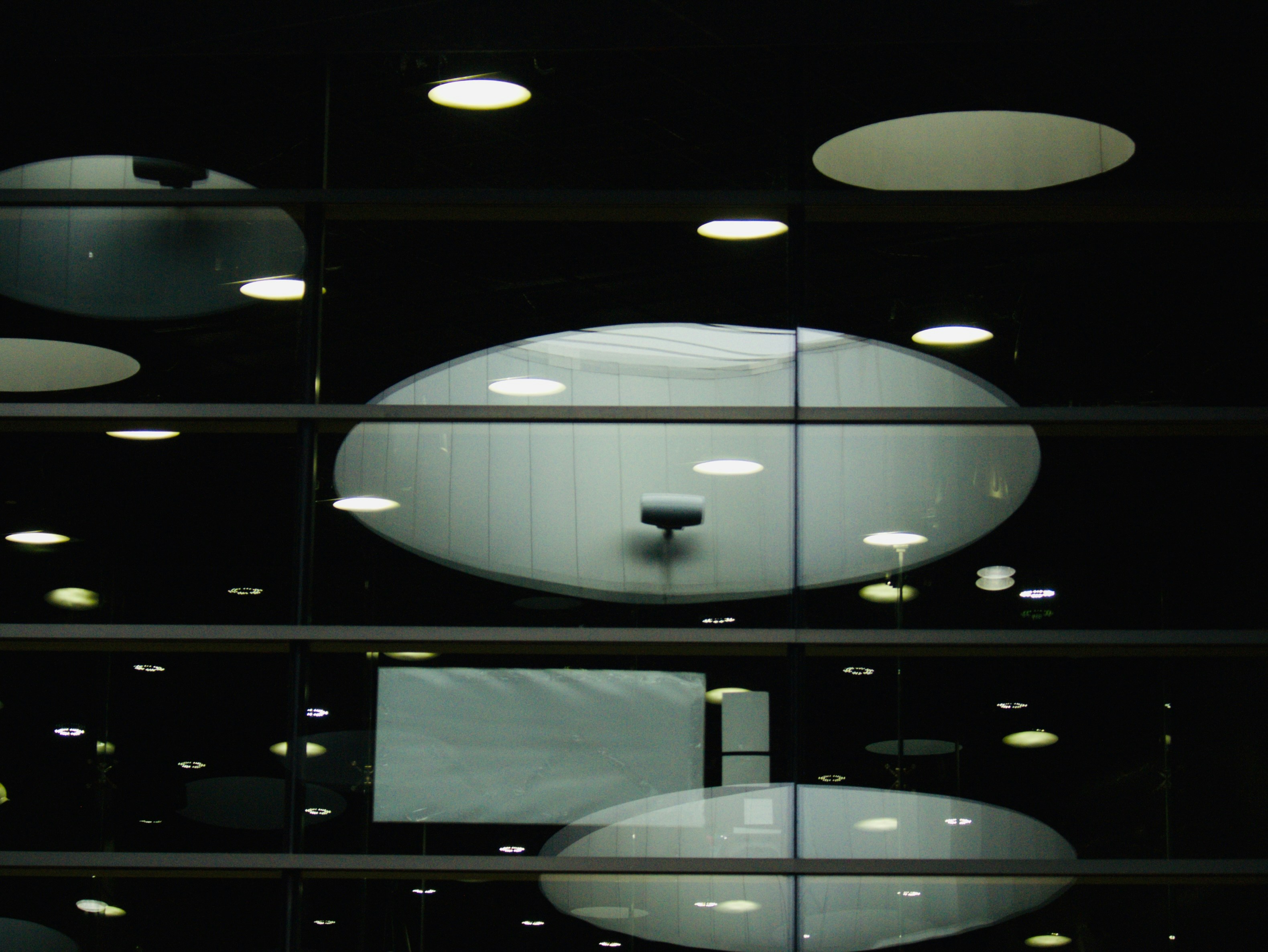 Overhead Circles Through Glass: Modern Lobby Lights Reflected