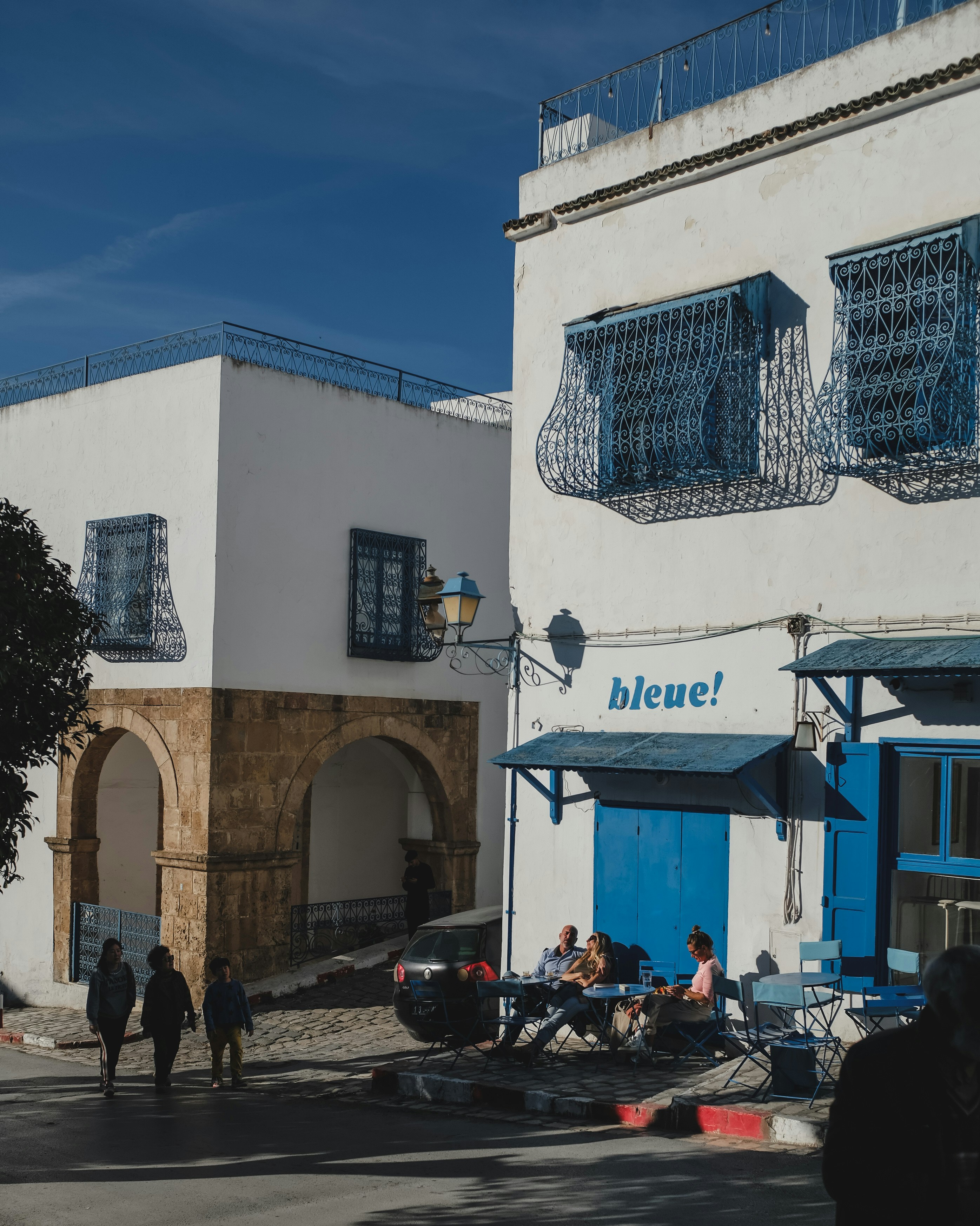 Blue Sign, White Archway: Street Café in Tuneful Light
