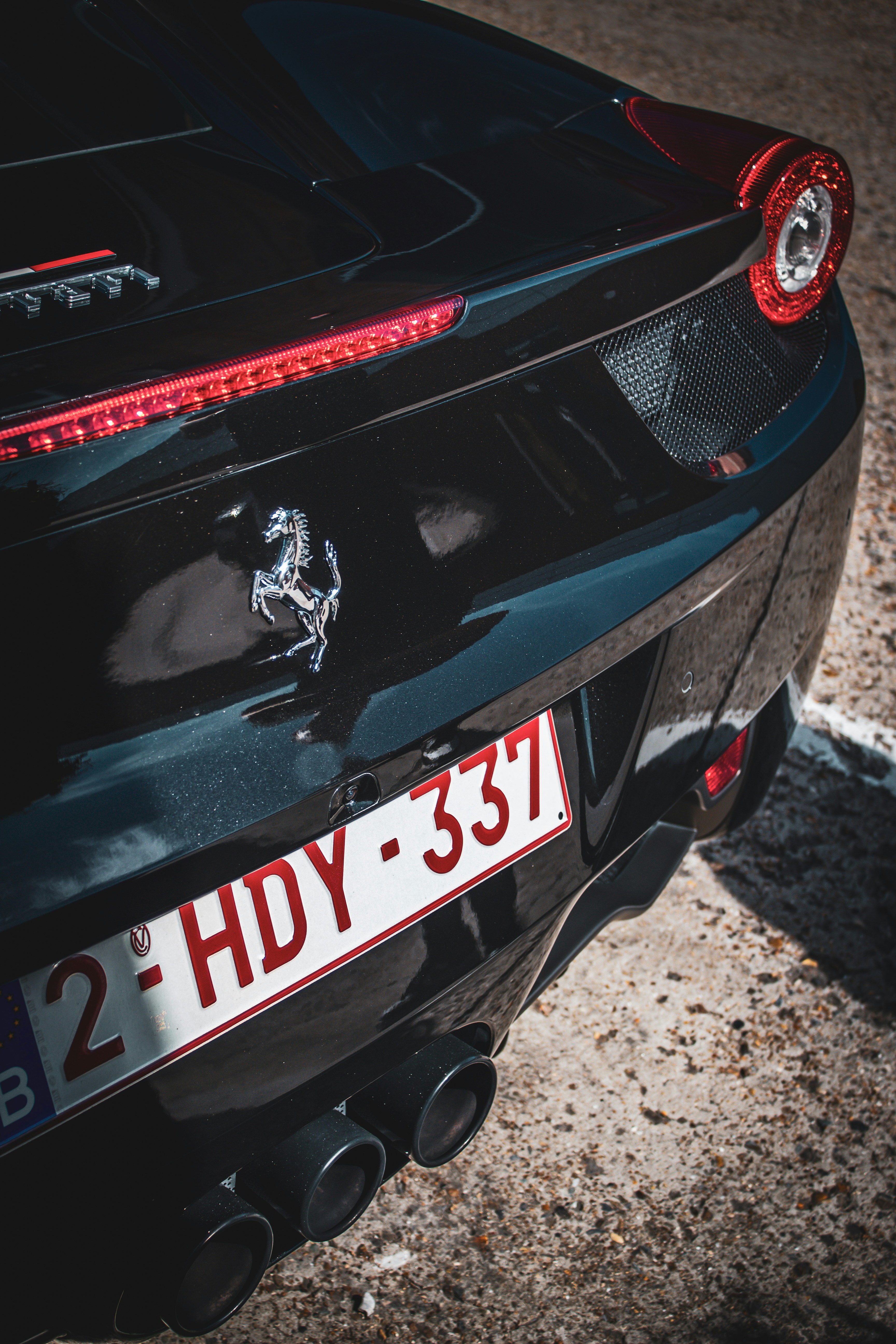 Rear View of a Black Ferrari: Emblem, Taillights, and Quad Exhausts