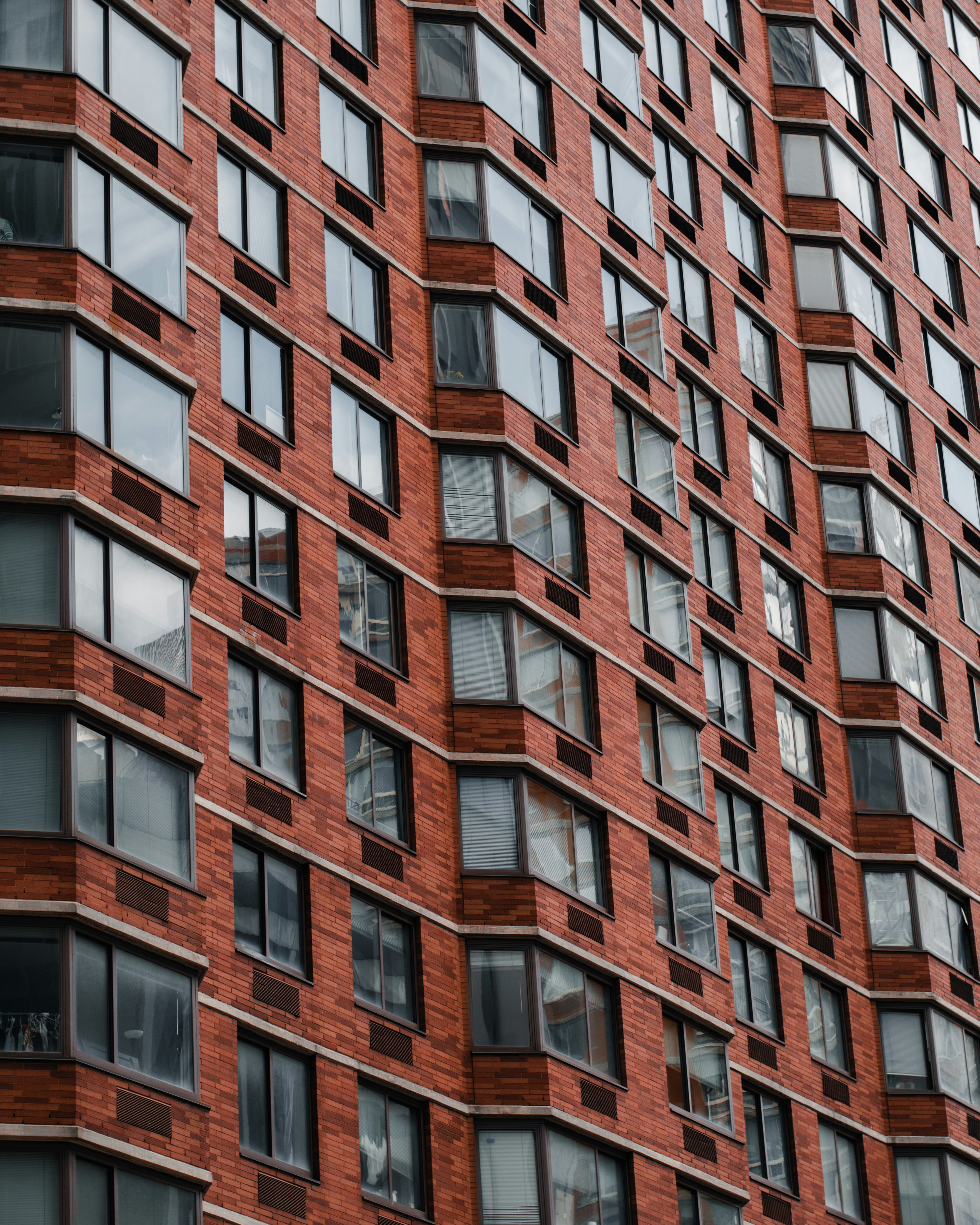 Uniform red brick facade with diagonal window rows creating a rhythmic pattern and depth.