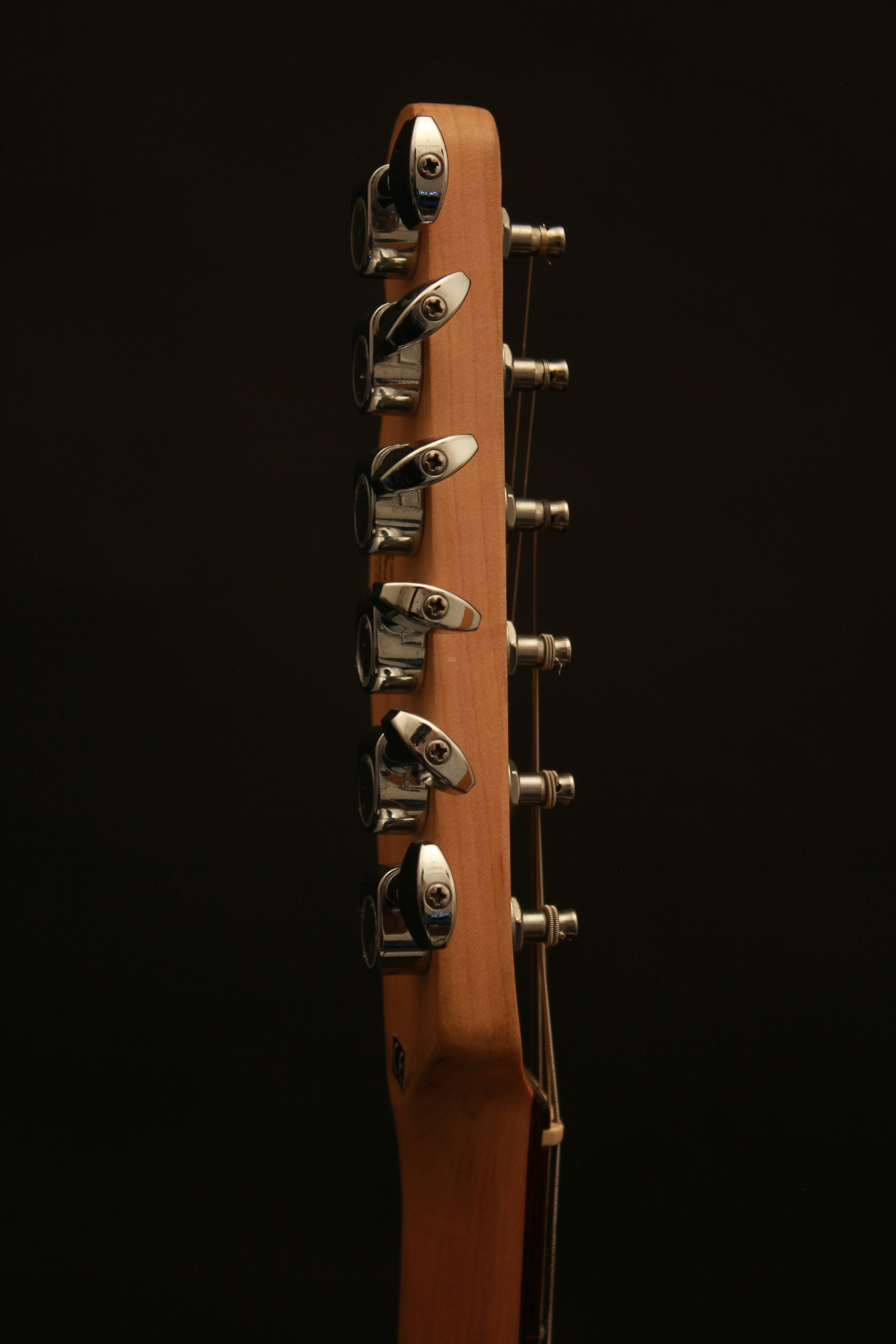 The Left-Handed Phase: A Guitar Headstock in Warm Spotlight