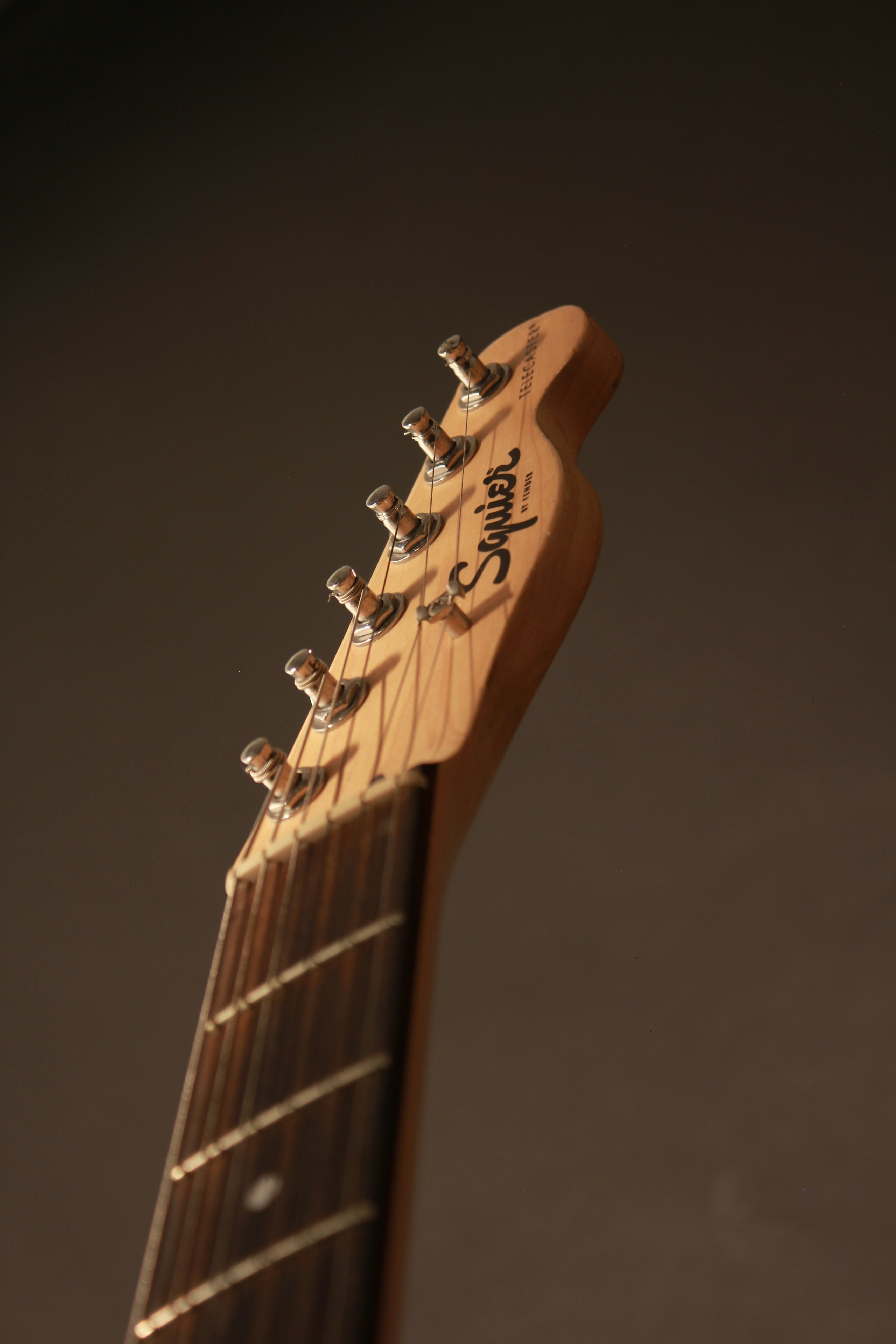 Close-up of a guitar headstock under warm studio light