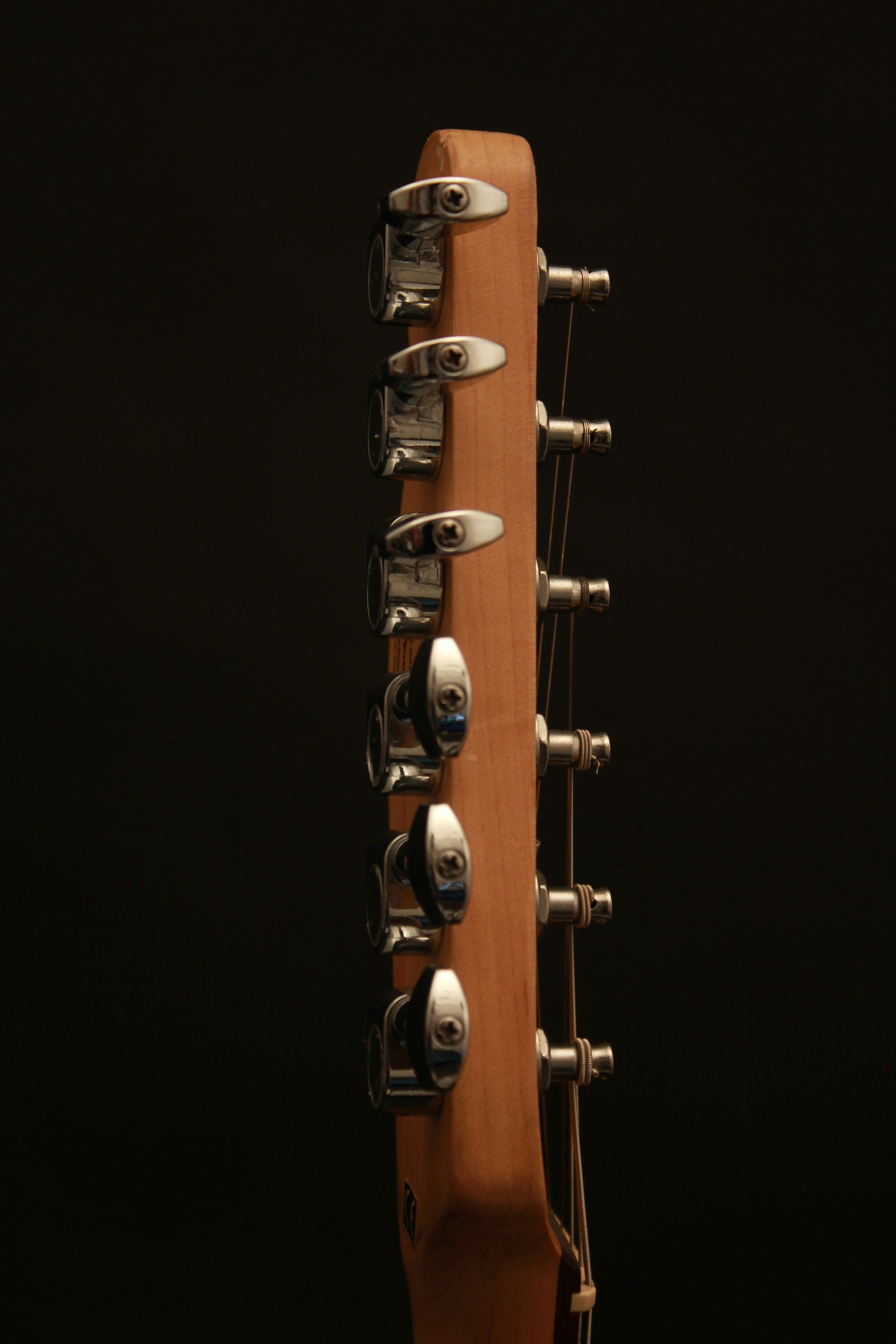 Close-up of a guitar headstock in warm studio light