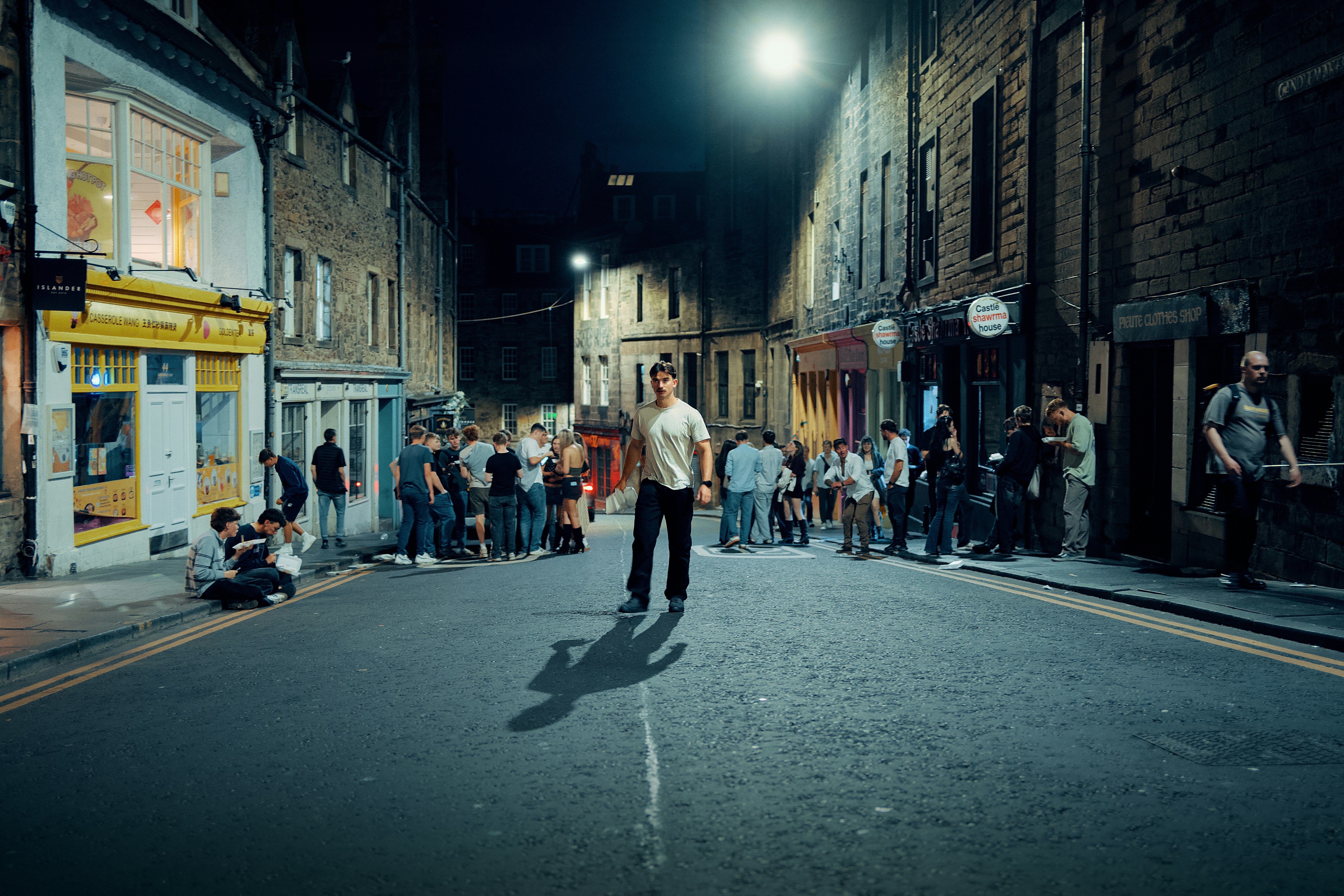 Midnight Street Portrait: A Lonesome Figure in a Lively Lane
