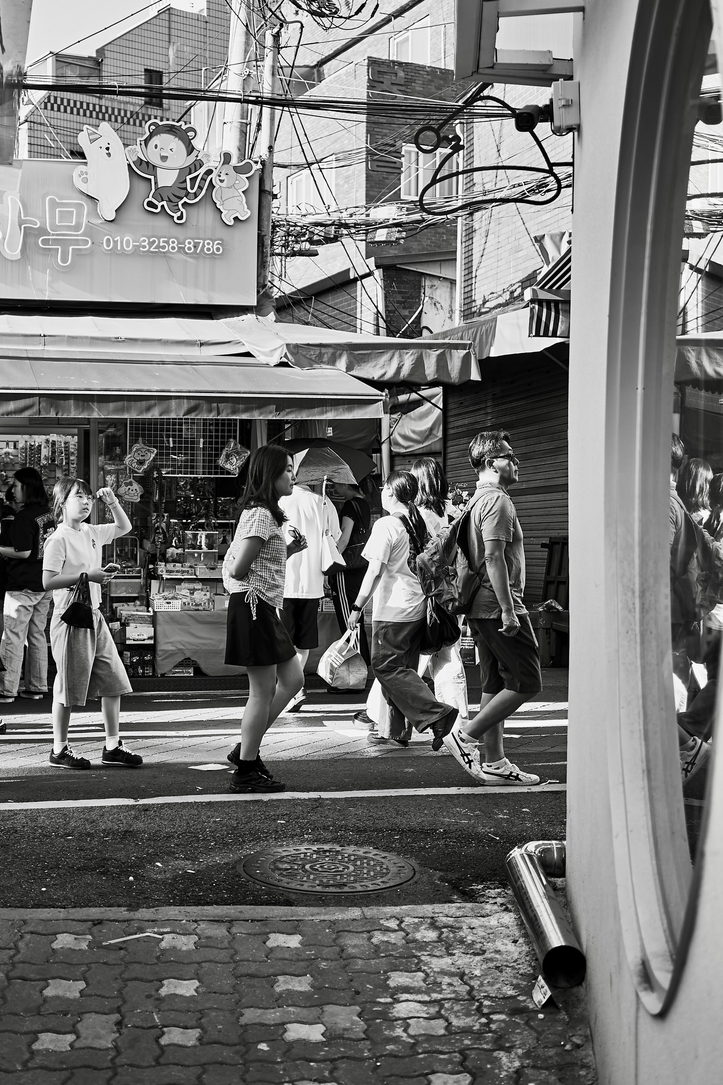 Crowded Street in Monochrome: Pedestrians Passing a Market Front