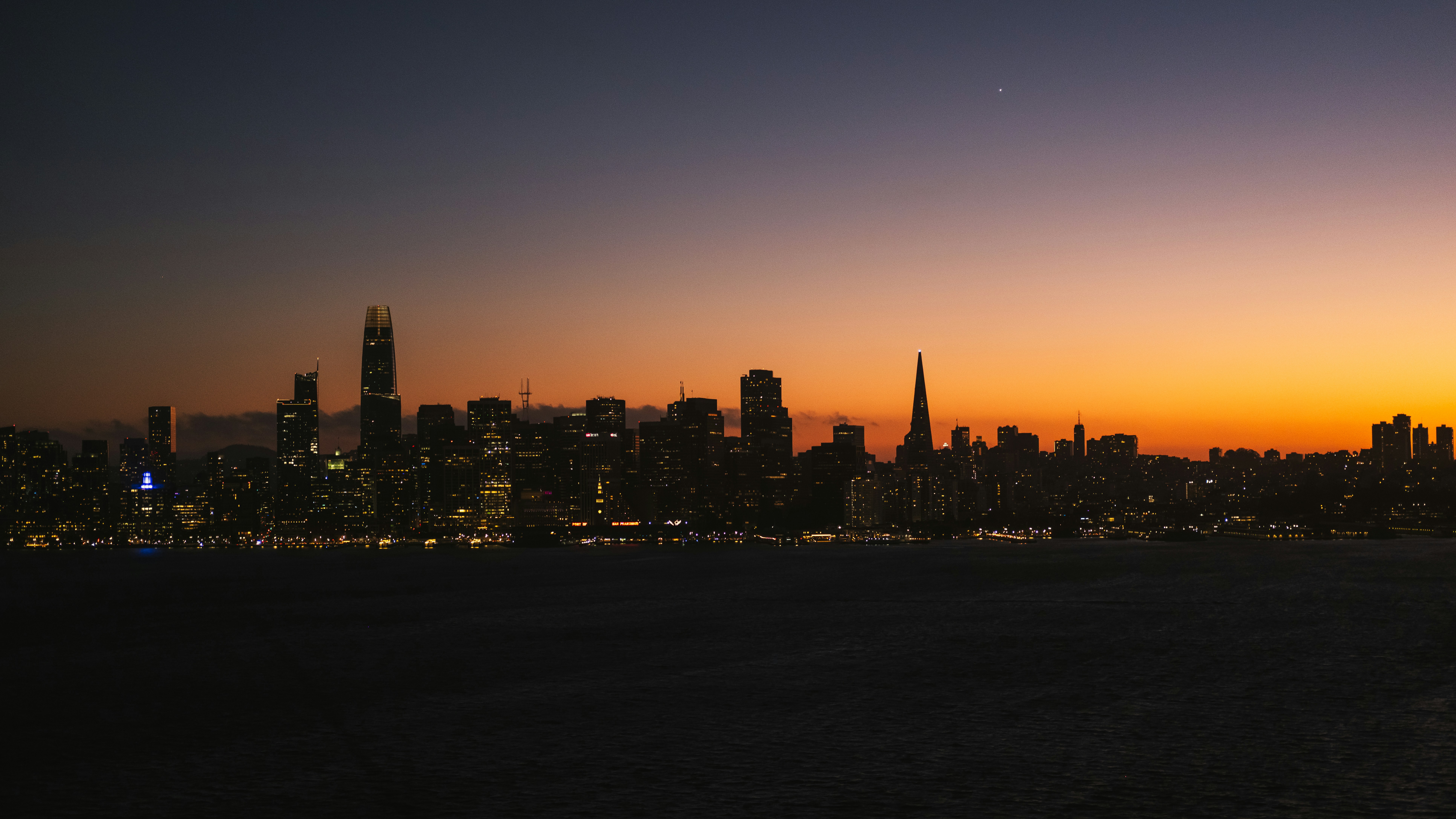 Twilight Skyline: City Lights Awakening Over Calm Water