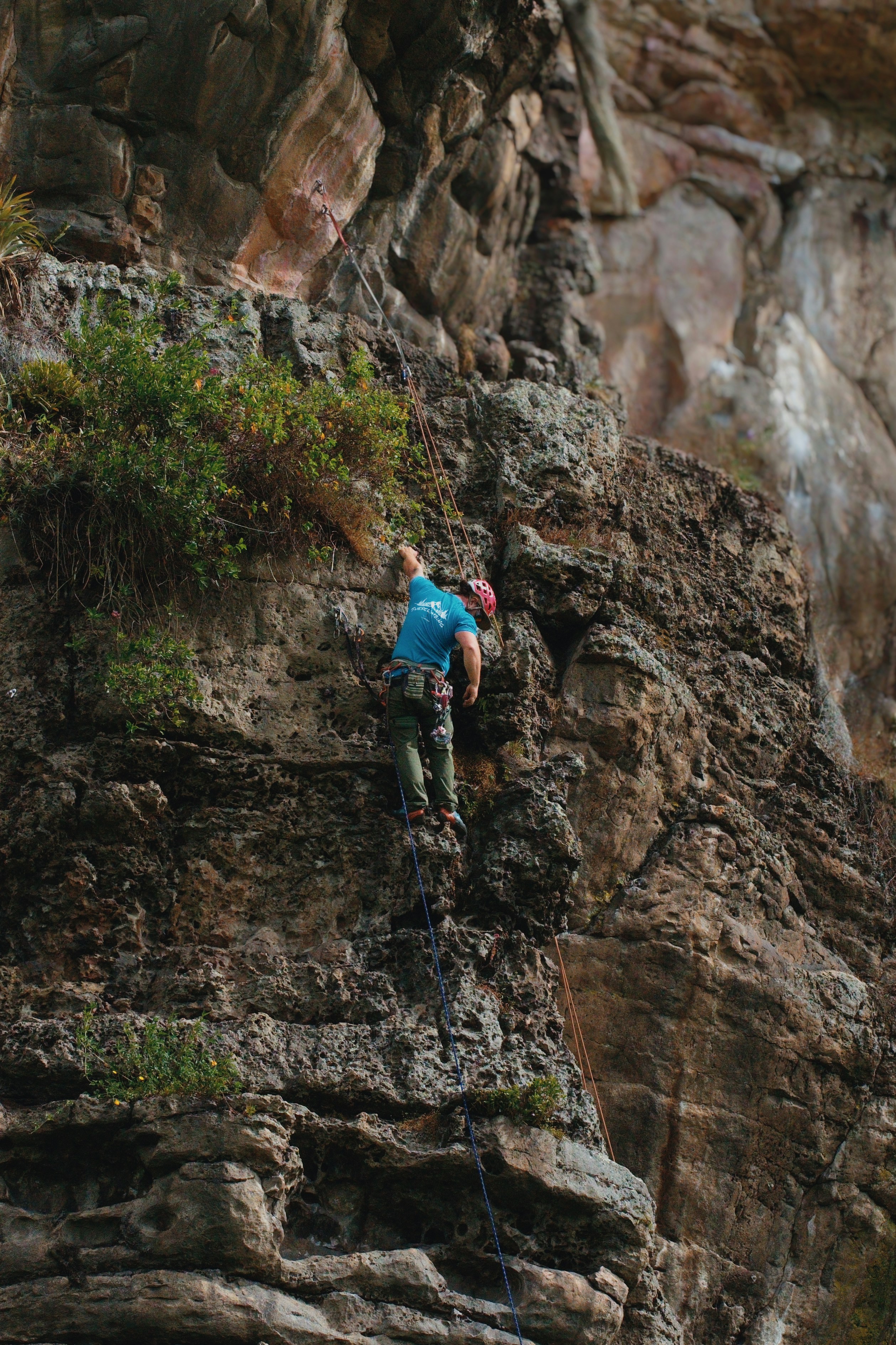 Climber Ascends a Rugged Rock Face Beneath a Craggy Overhang