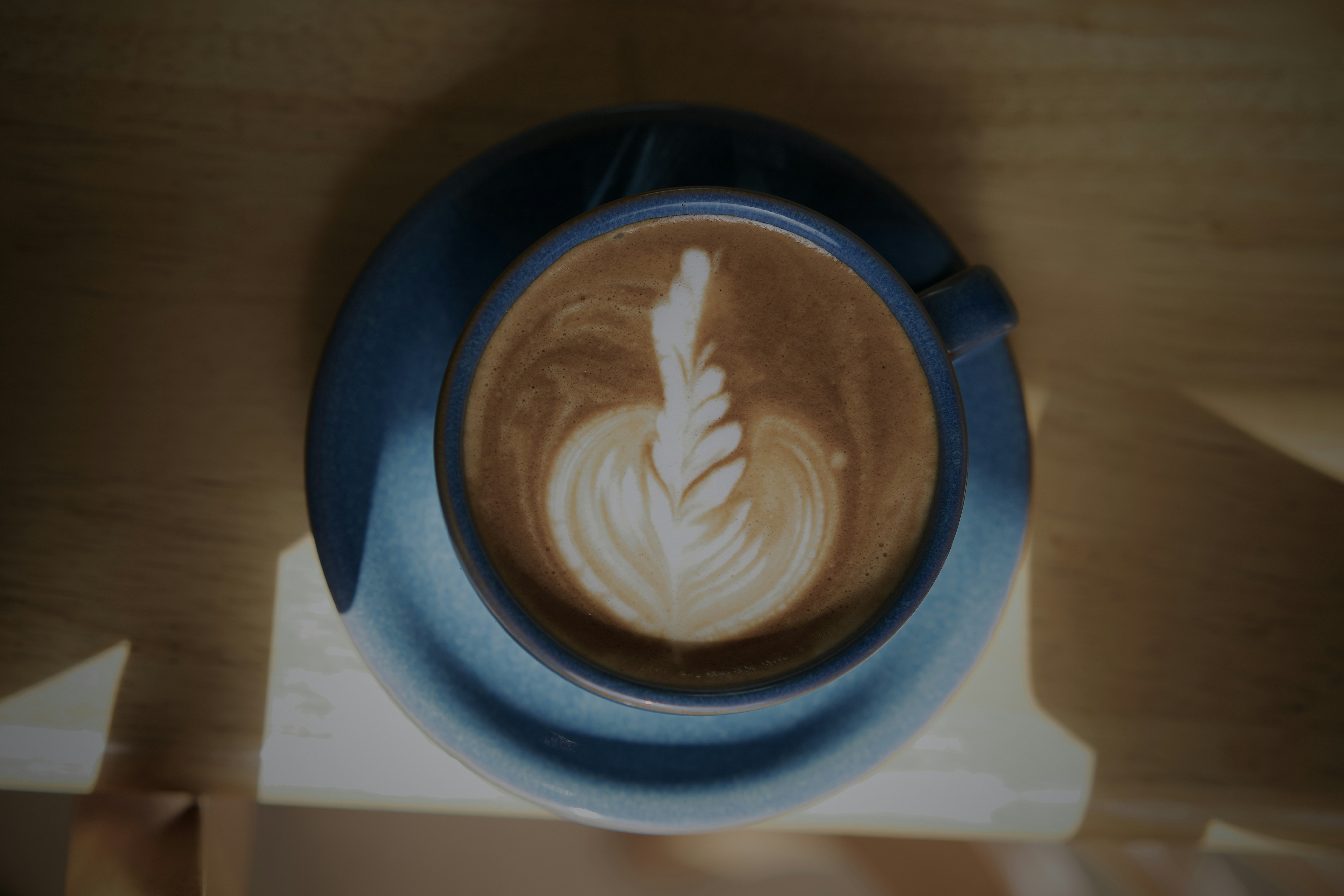 Blue Ceramic Cup of Latte with Foamy Heart on a Wooden Table