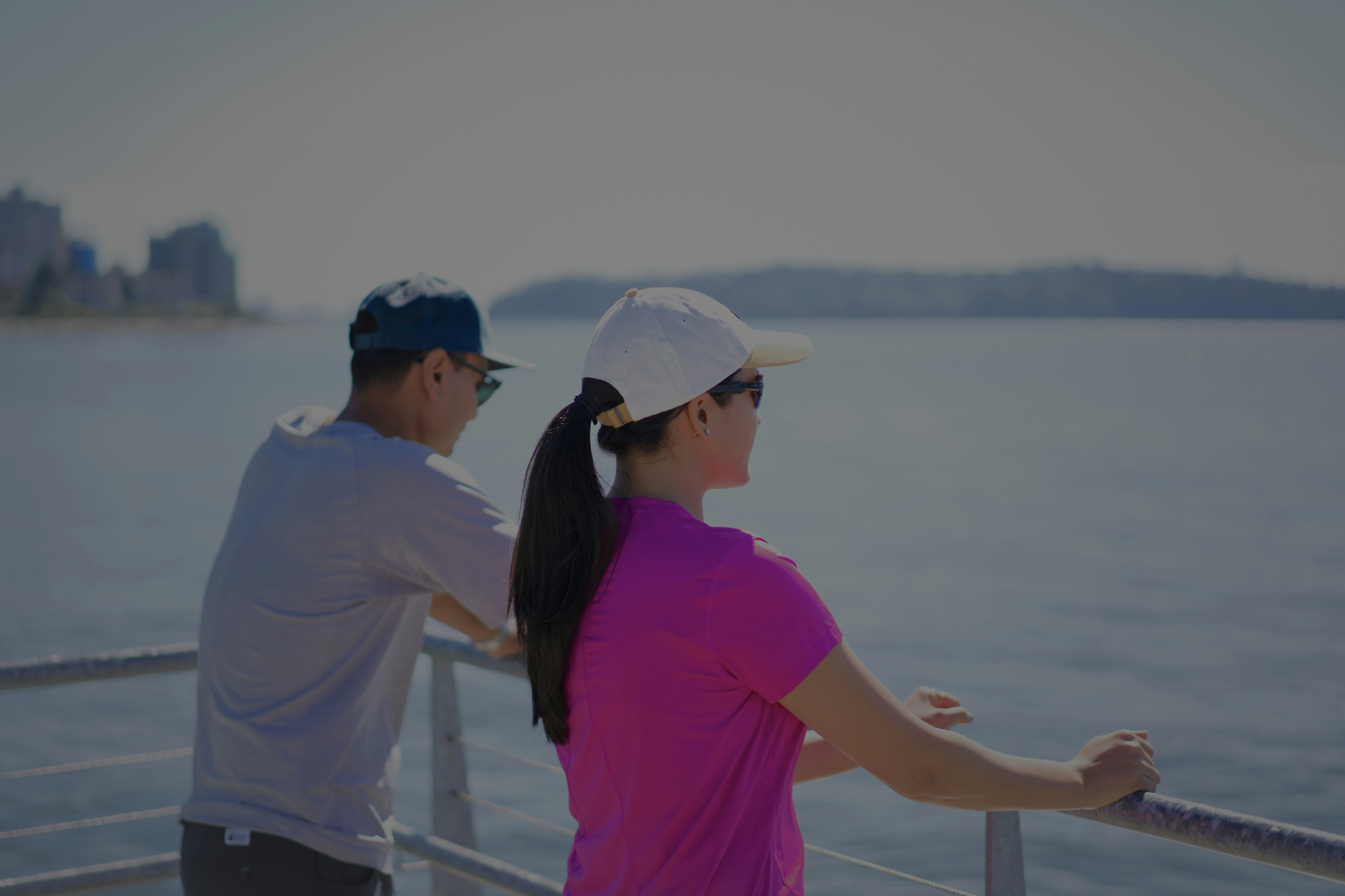 Close-up of a pair on a seaside railing with distant horizon
