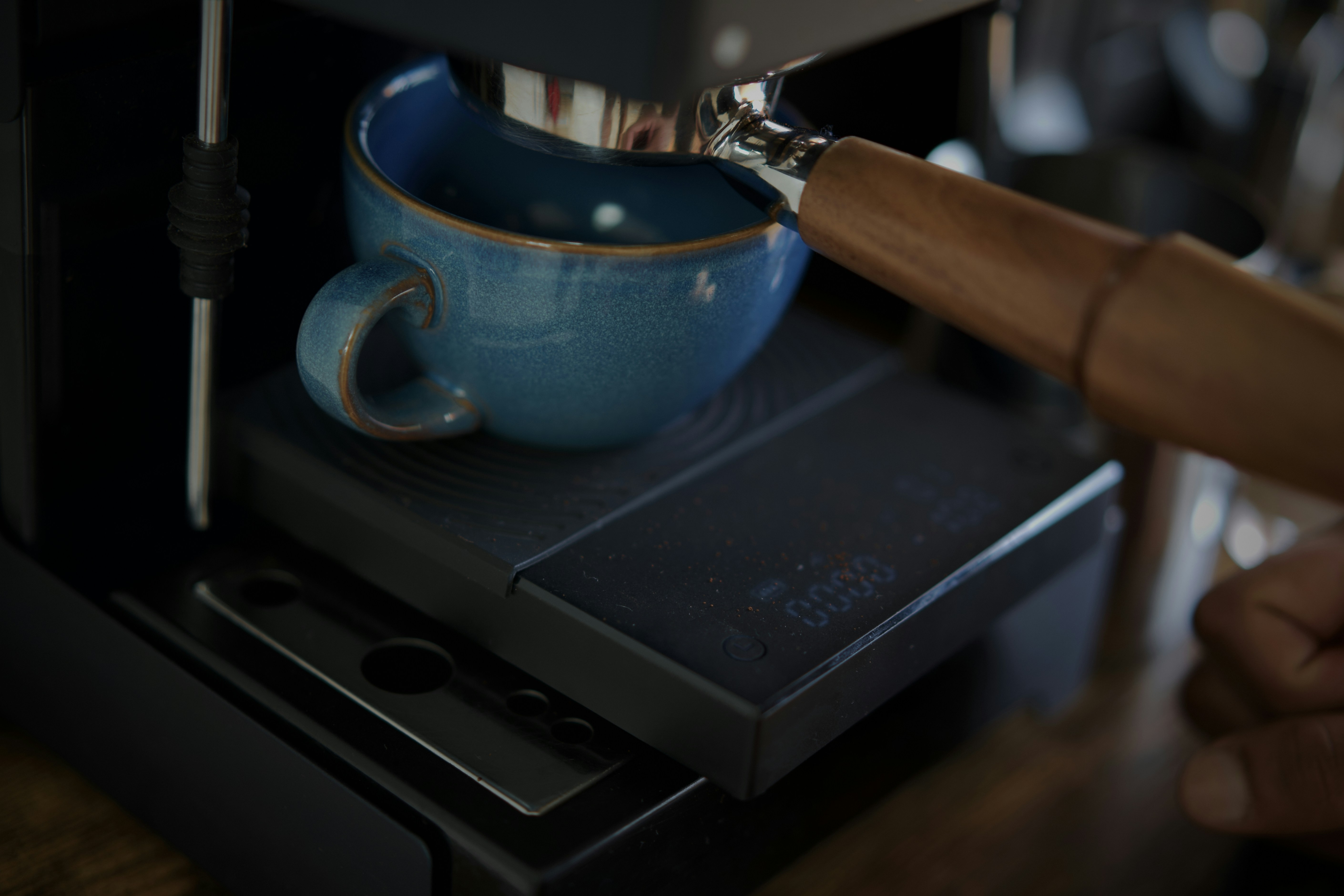 Blue mug meets espresso ritual under a wooden-handled tap