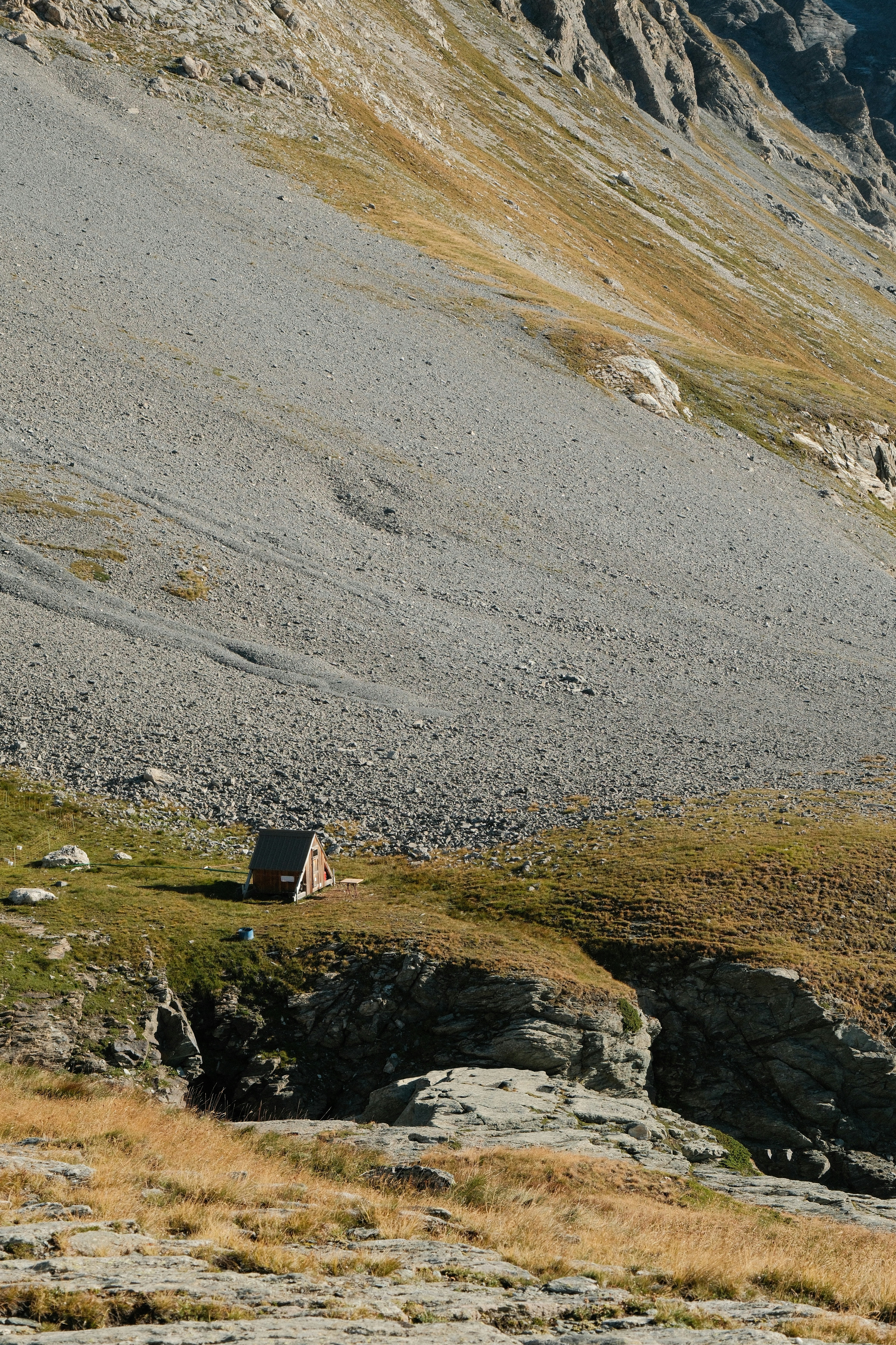 A Lone Cabin Amidst Sloping Tundra and Granite Cliffs