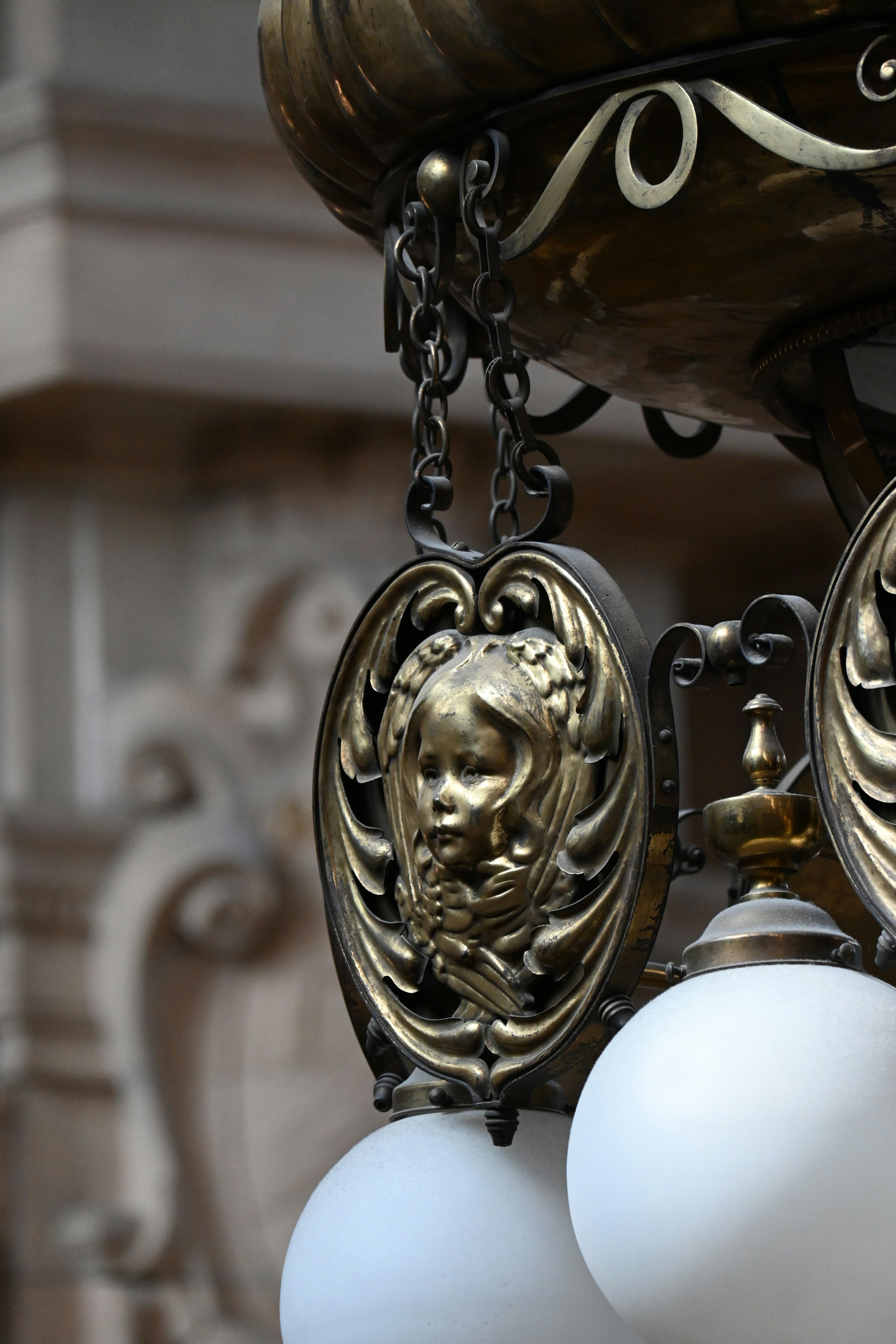 Ornate Sculpture Necklace: A Brass Medallion with Angelic Portrait Gracing a Lamp
