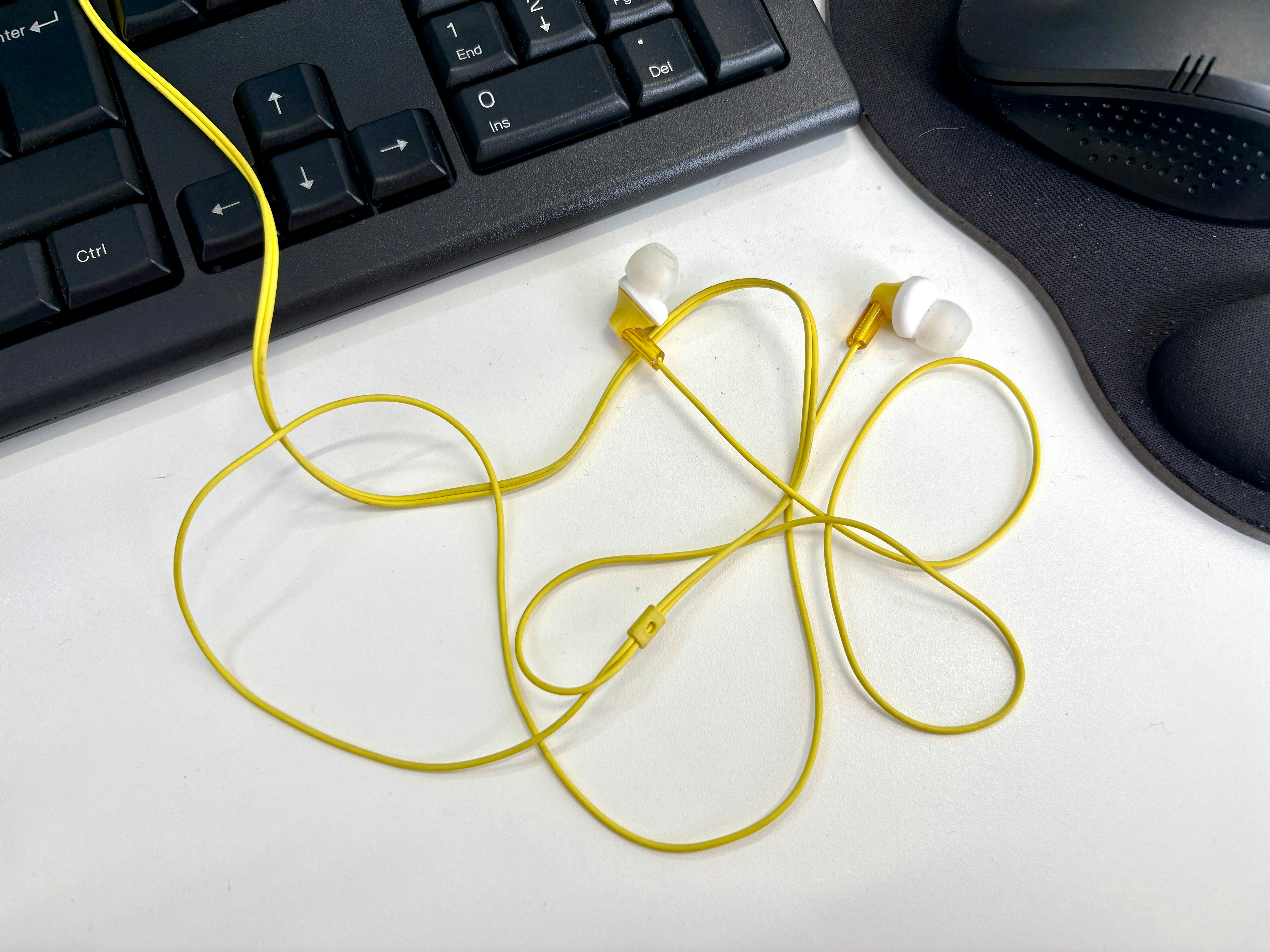 Yellow Earbuds on a Desk Amid Computer Gear
