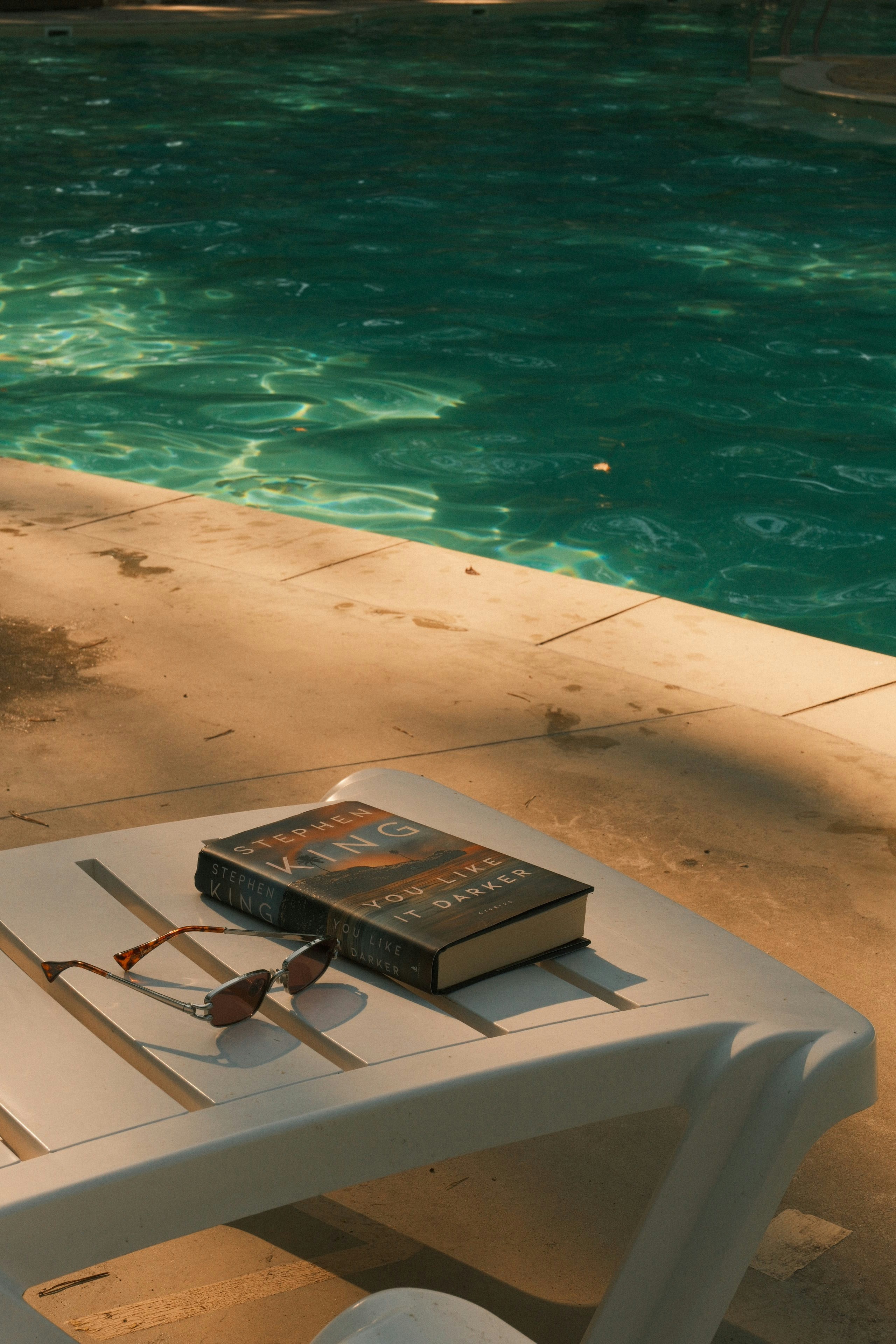 Relaxed afternoon by the pool: a book and sunglasses on a white table