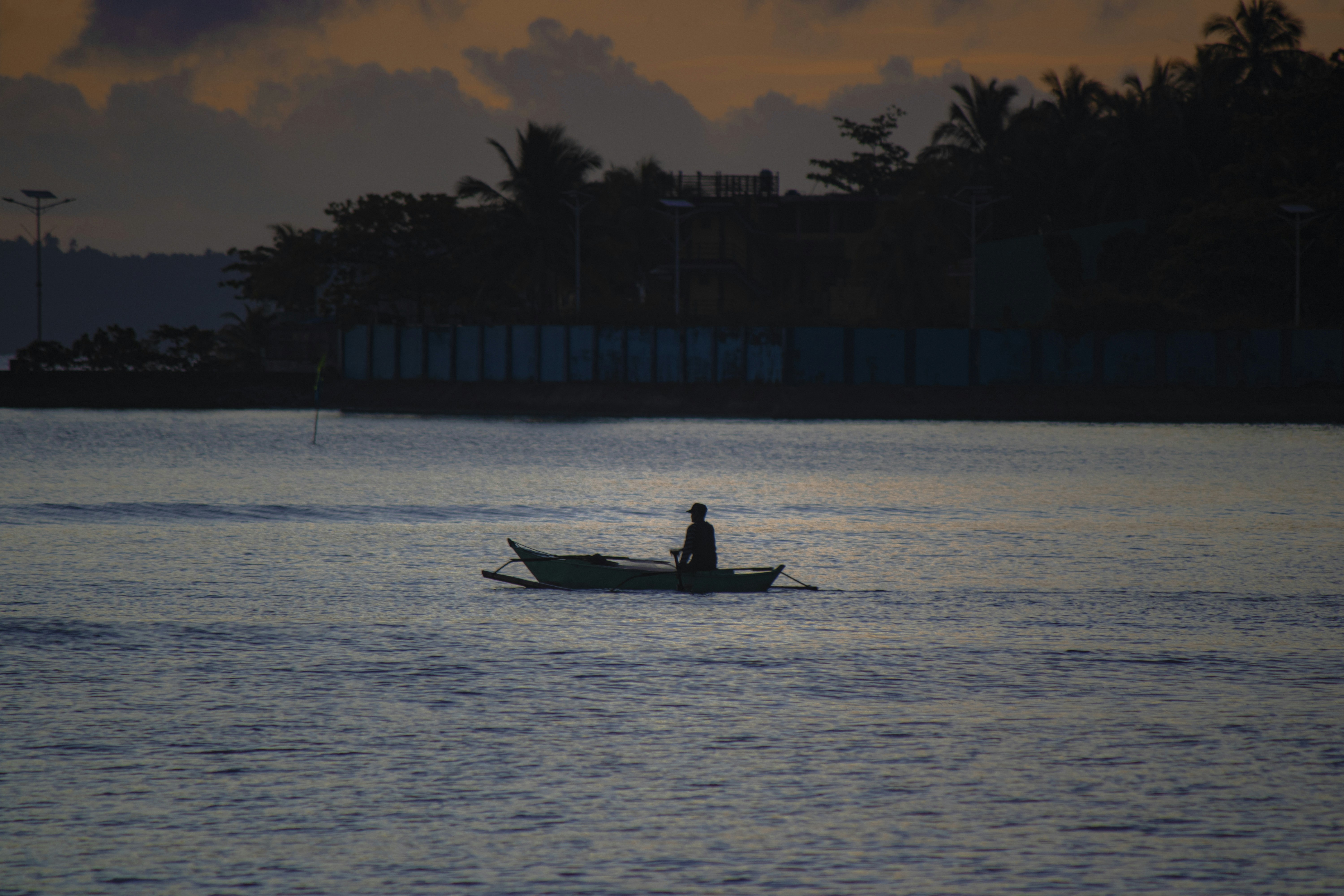 Silhouette Afloat: A Lone Figure in a Quiet Harbour
