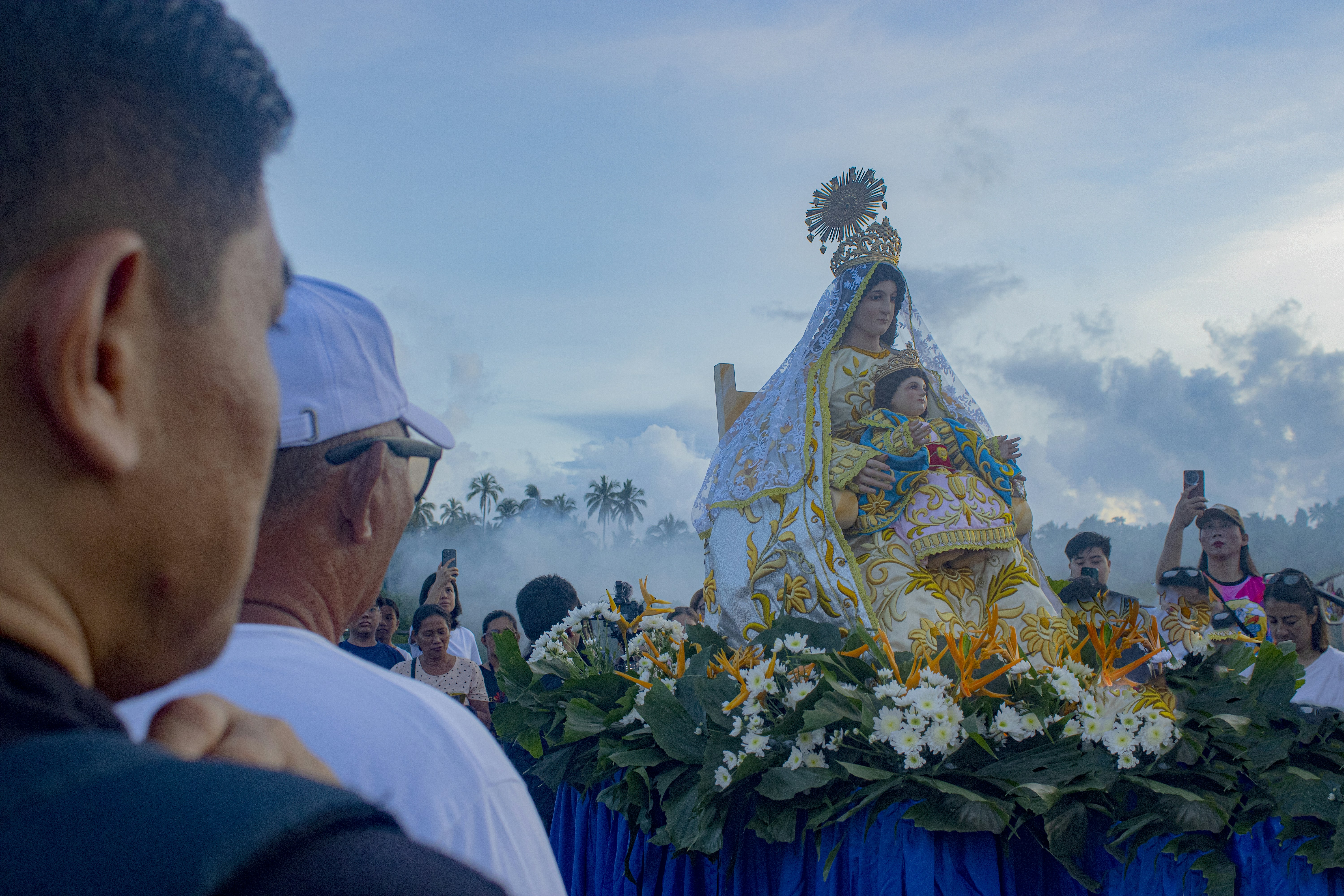 Procession of Light: A Marian statue floats above a floral altar amid a crowd