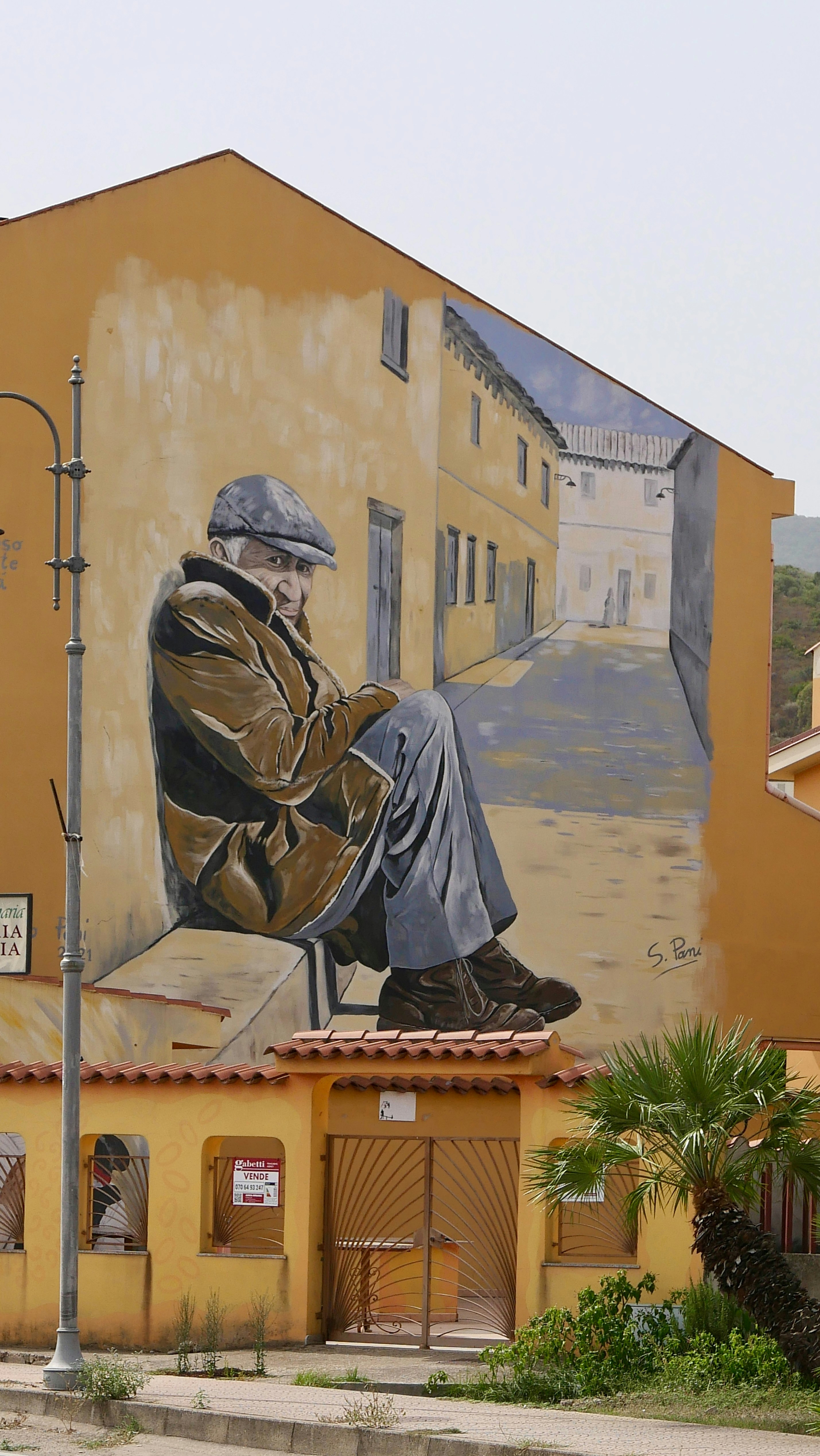 The Somber Silhouette: A Mural Portrait on a Sunlit Calle
