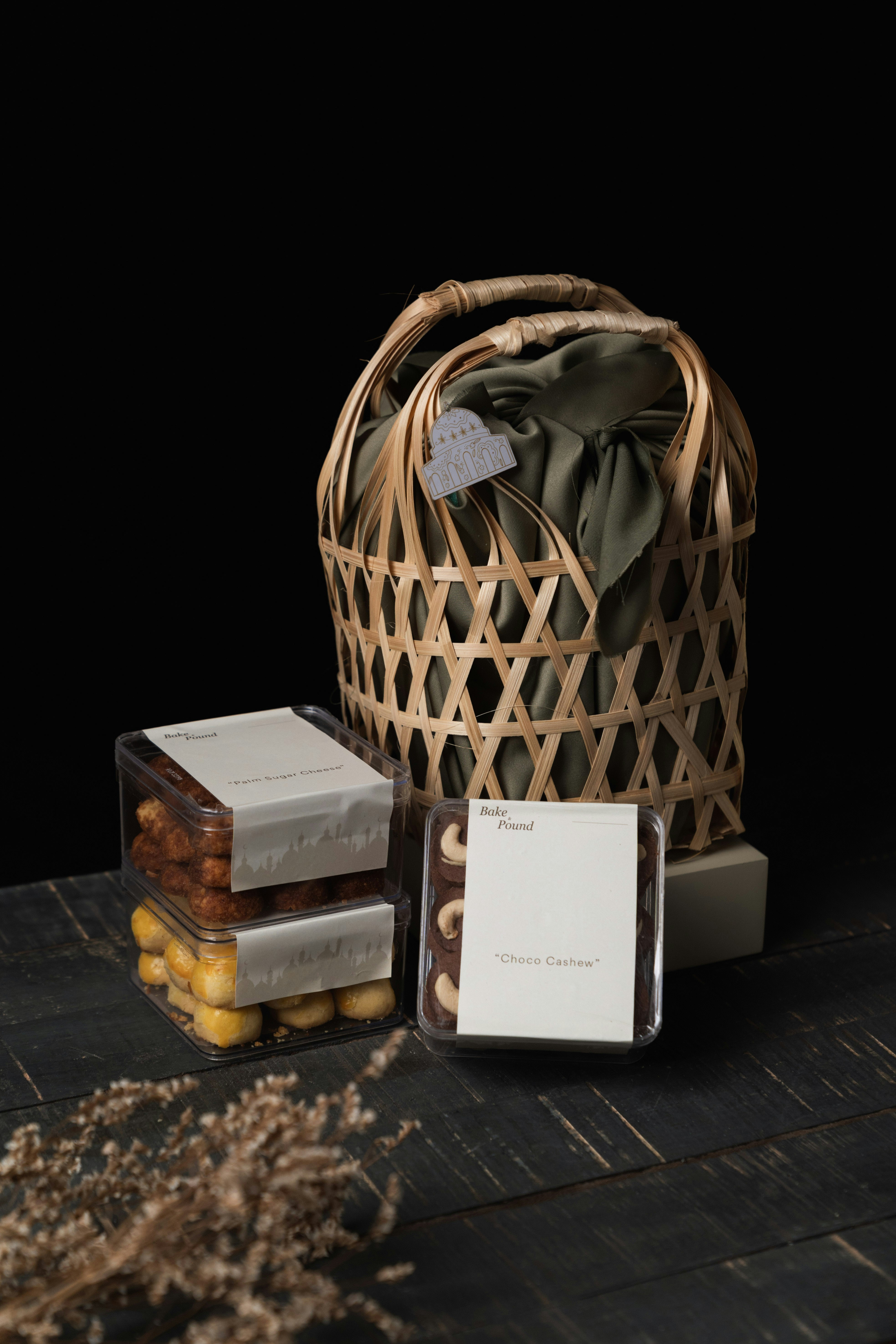 Basket woven with green cloth and neatly arranged confections on a dark wooden surface