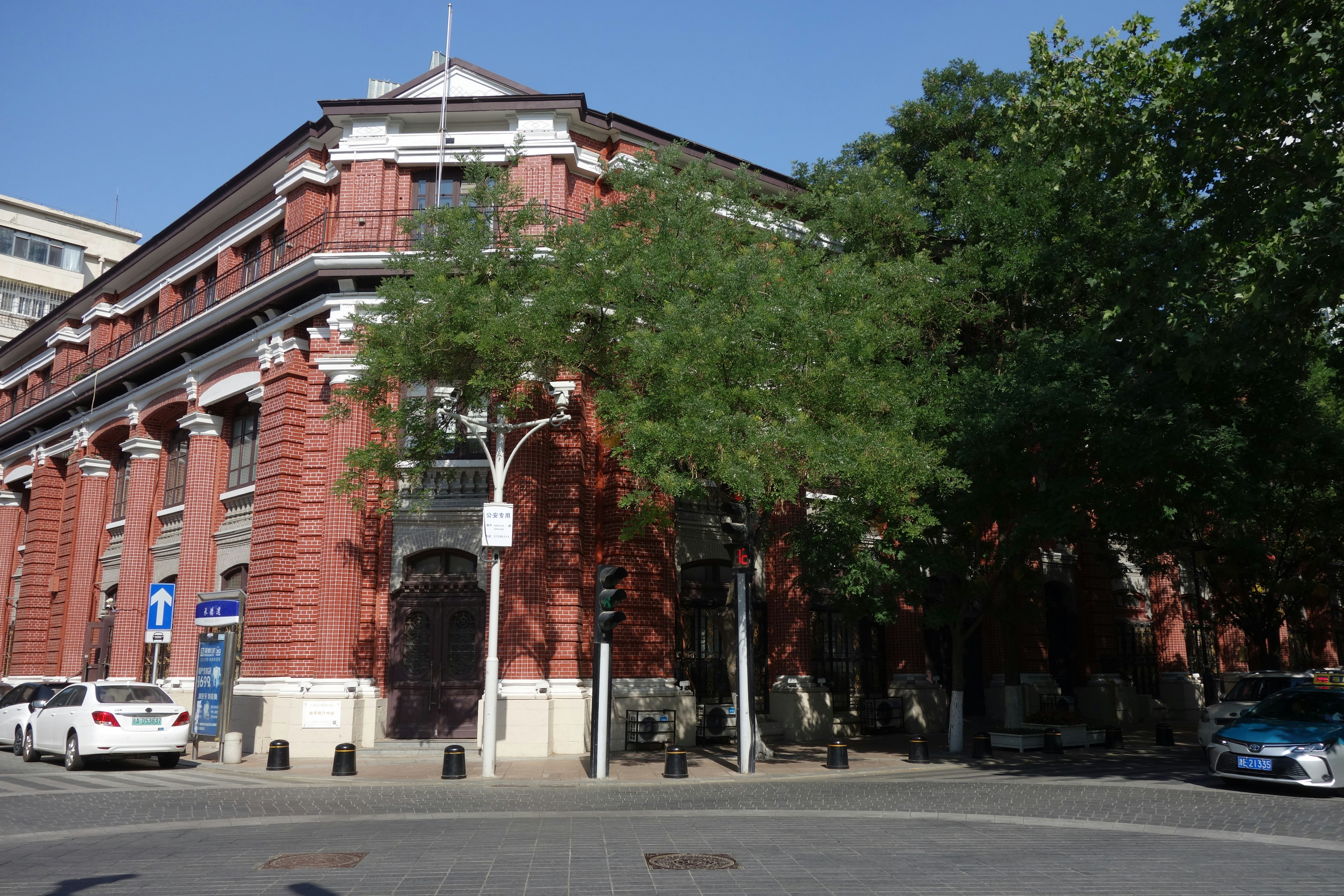 Red-brick Cornerstone: Sunlit Facade and Tree-lined Street