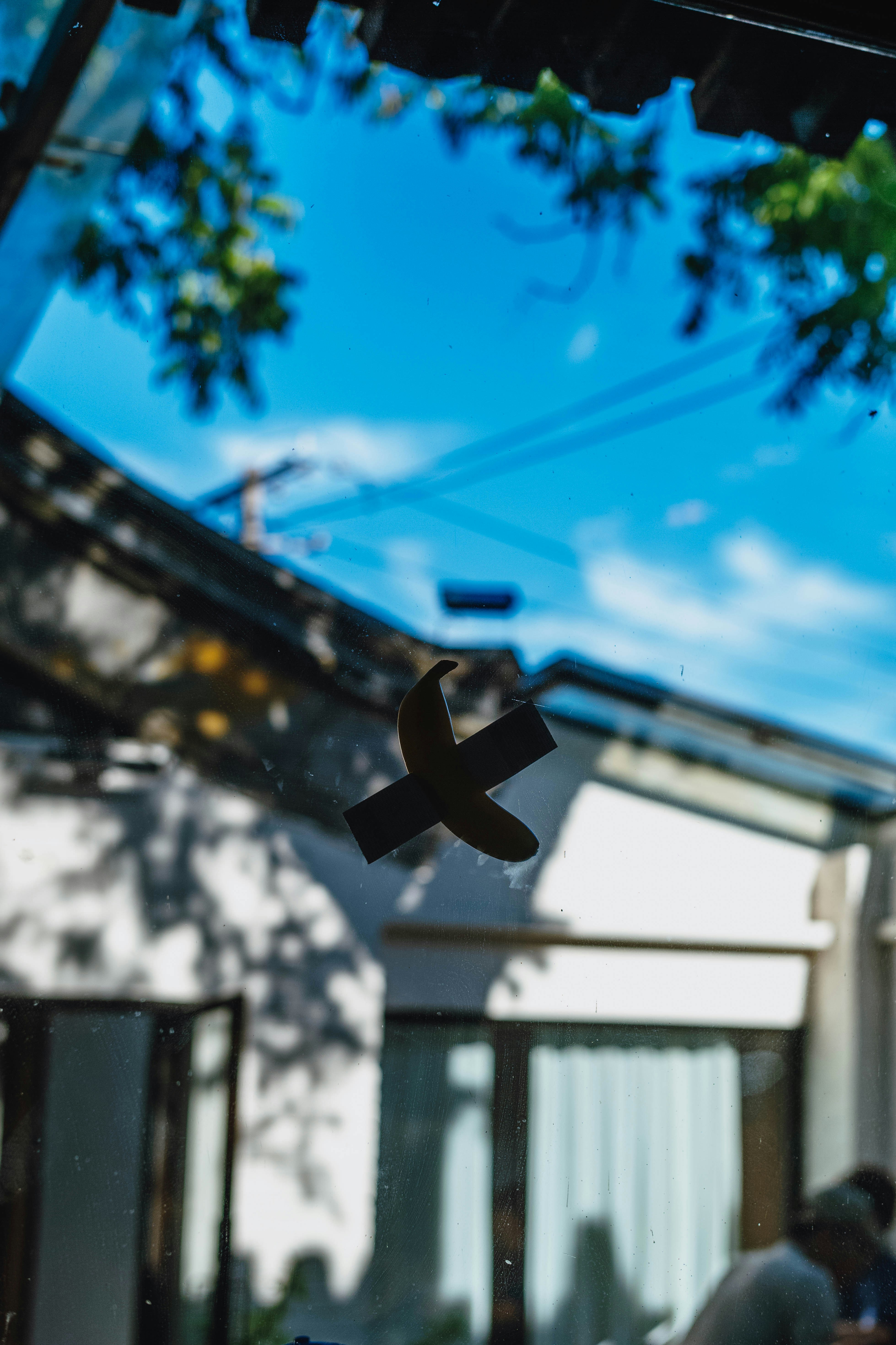 Floating Crescent on Glass: A Window Sign Against a Bright Sky