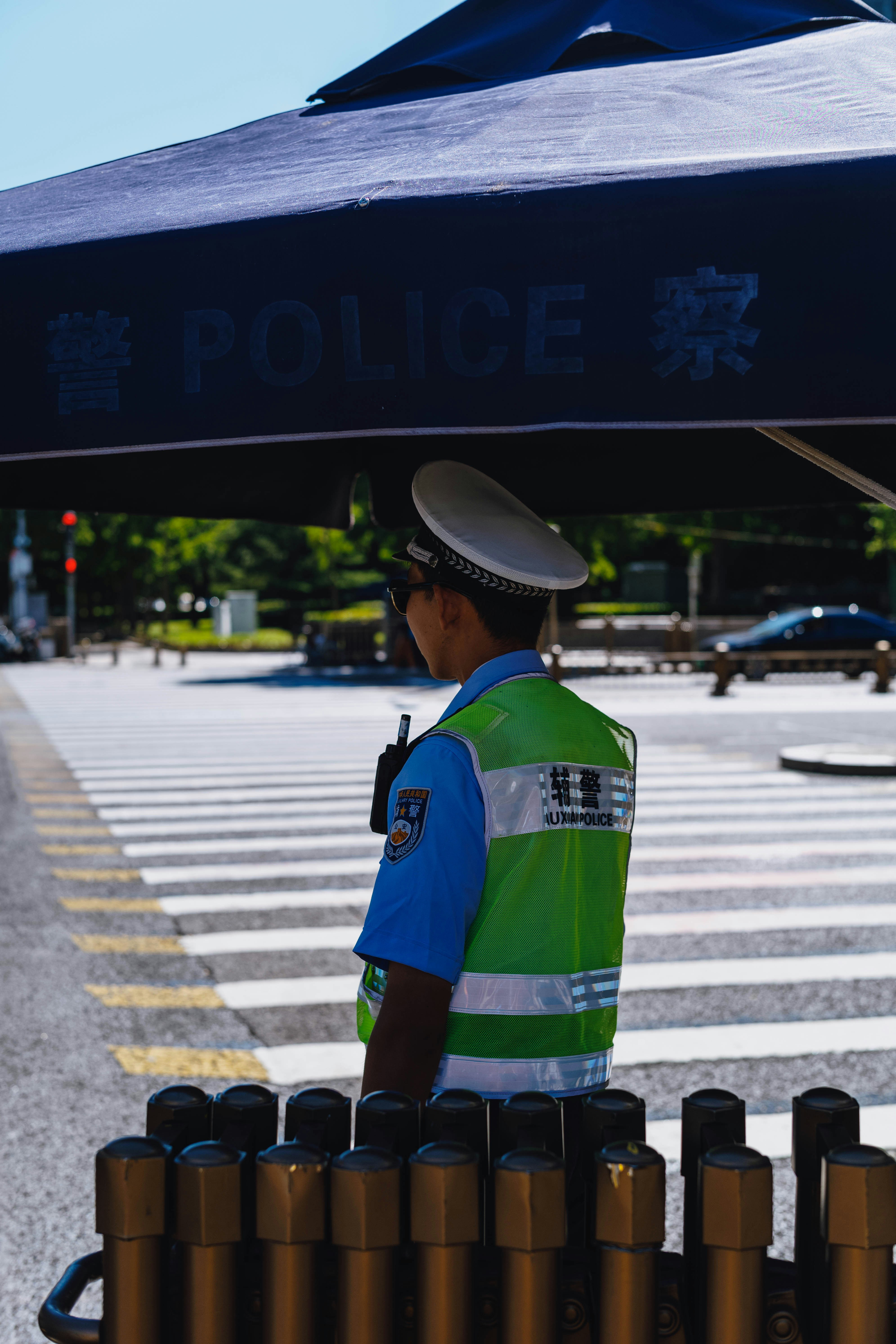 Guard in Neon Vest at a Crosswalk Under the Police Canopy