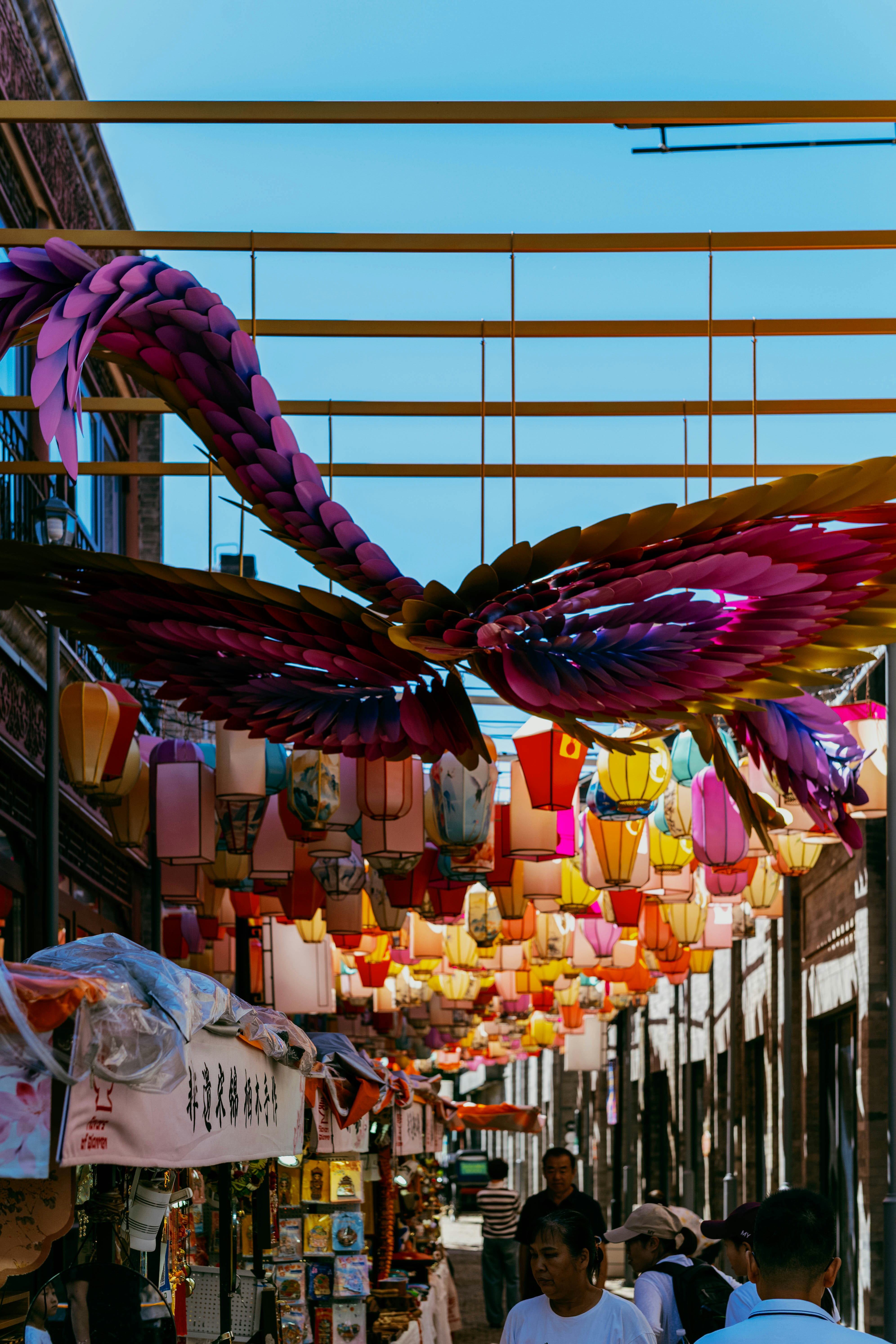 Colorful Winged Lanterns Over a Sunlit Market Lane