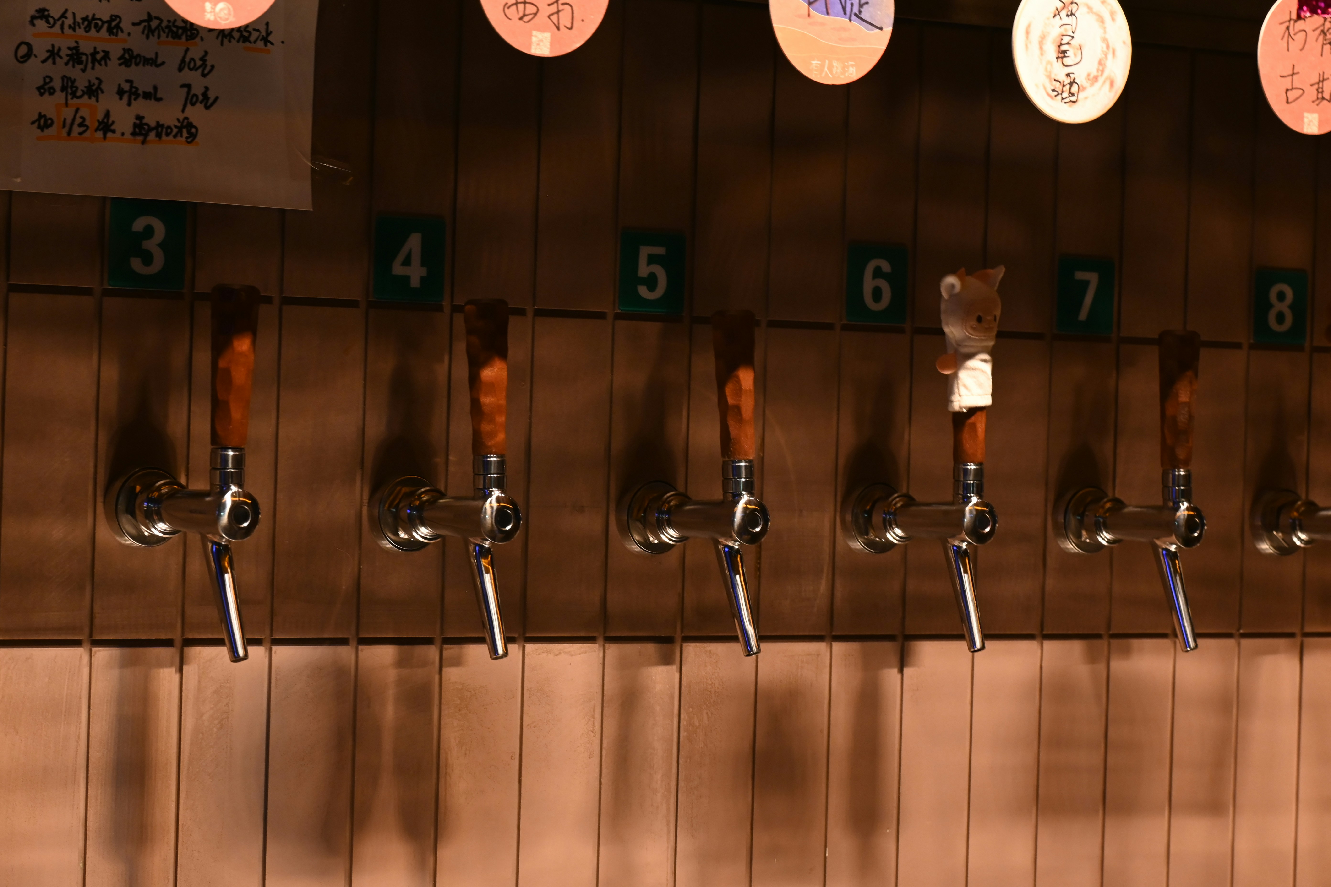 Row of beer taps with copper handles and hanging paper lanterns
