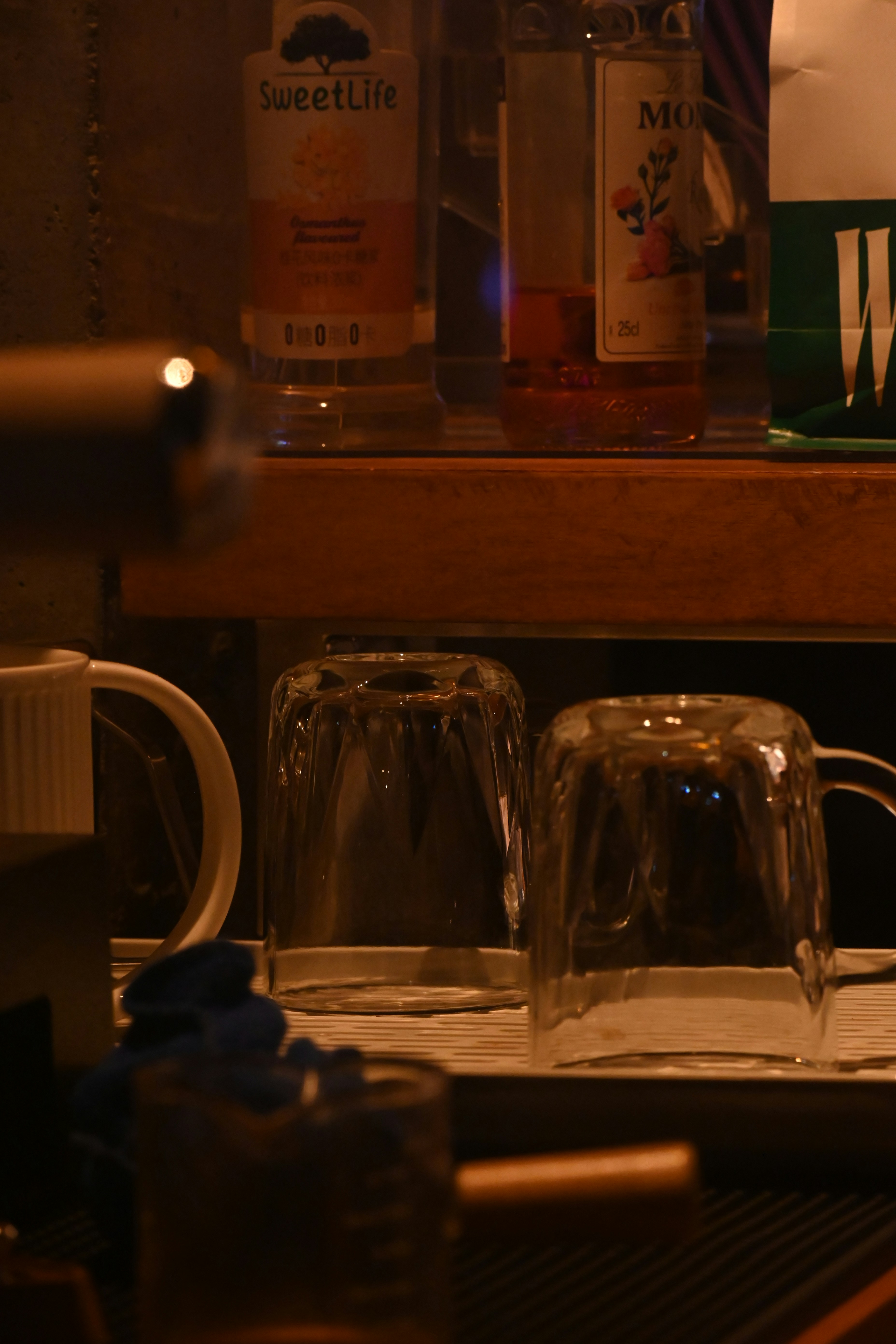 Dim Coffee Bar Echoes: Glasses, Mugs, and Bottles in Low Light