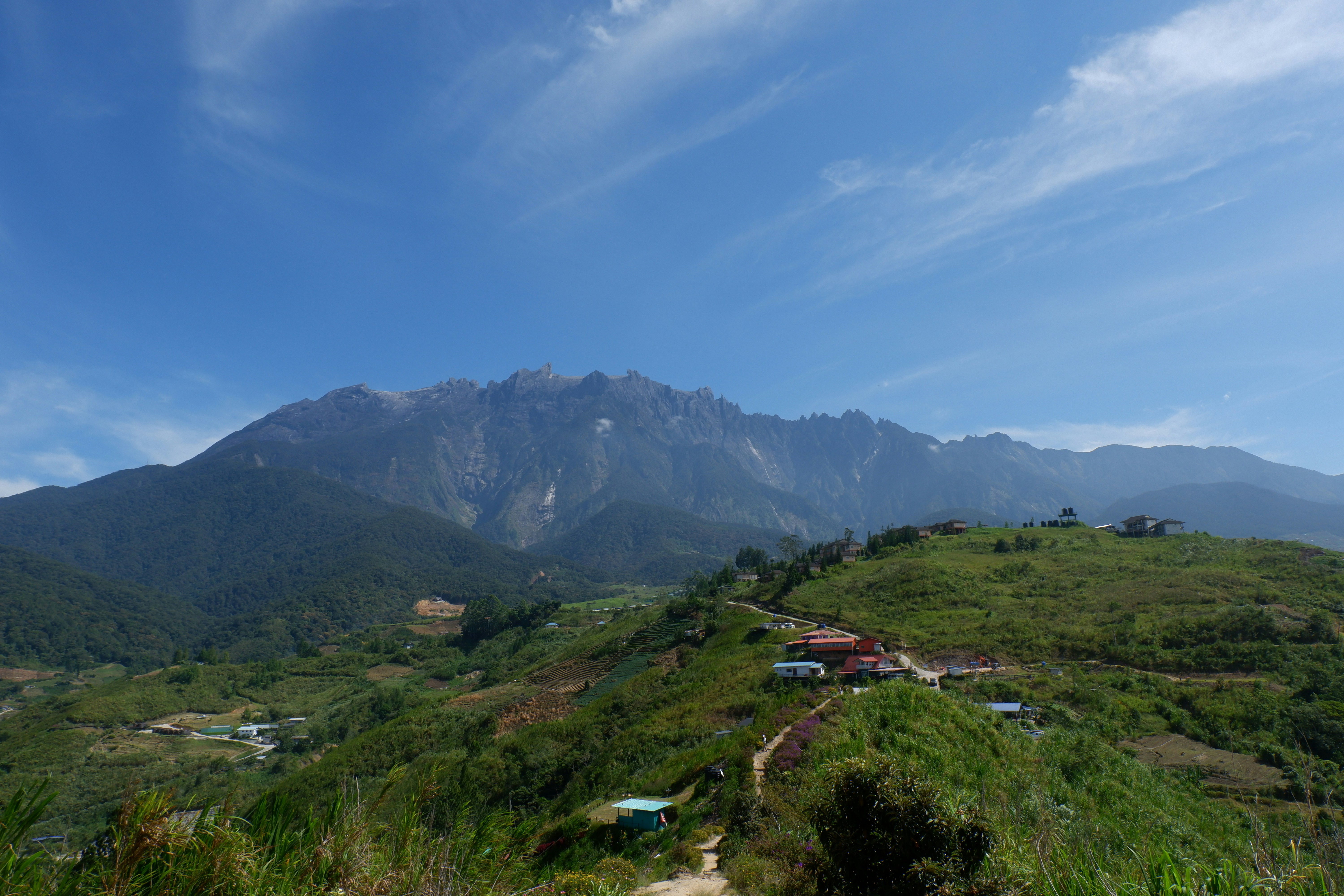 Hilltop Village Beneath a Prominent Mountain Ridge at Noon